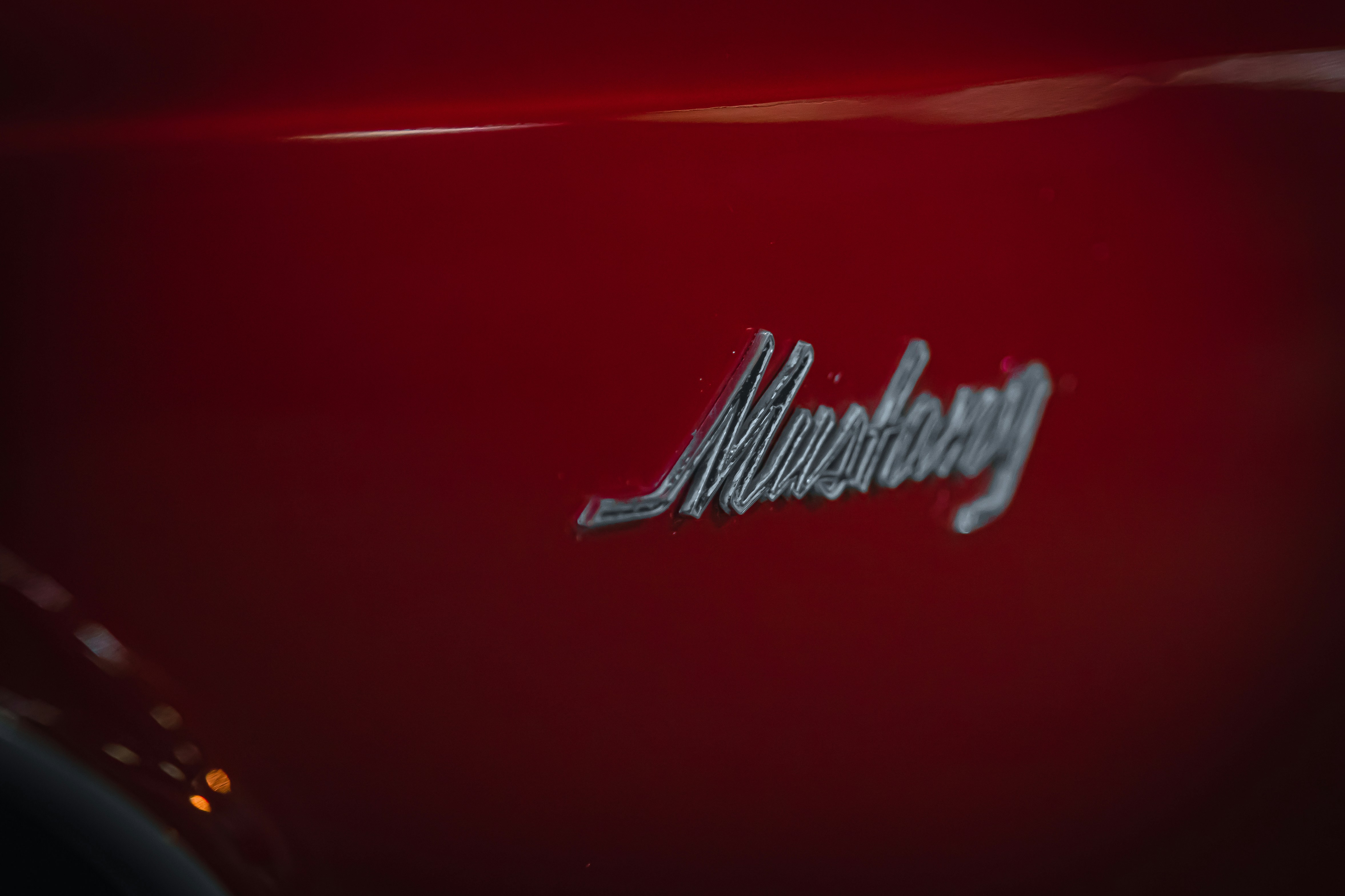 Emblem in Red: A Glinting Mustang Script on Glossy Surface