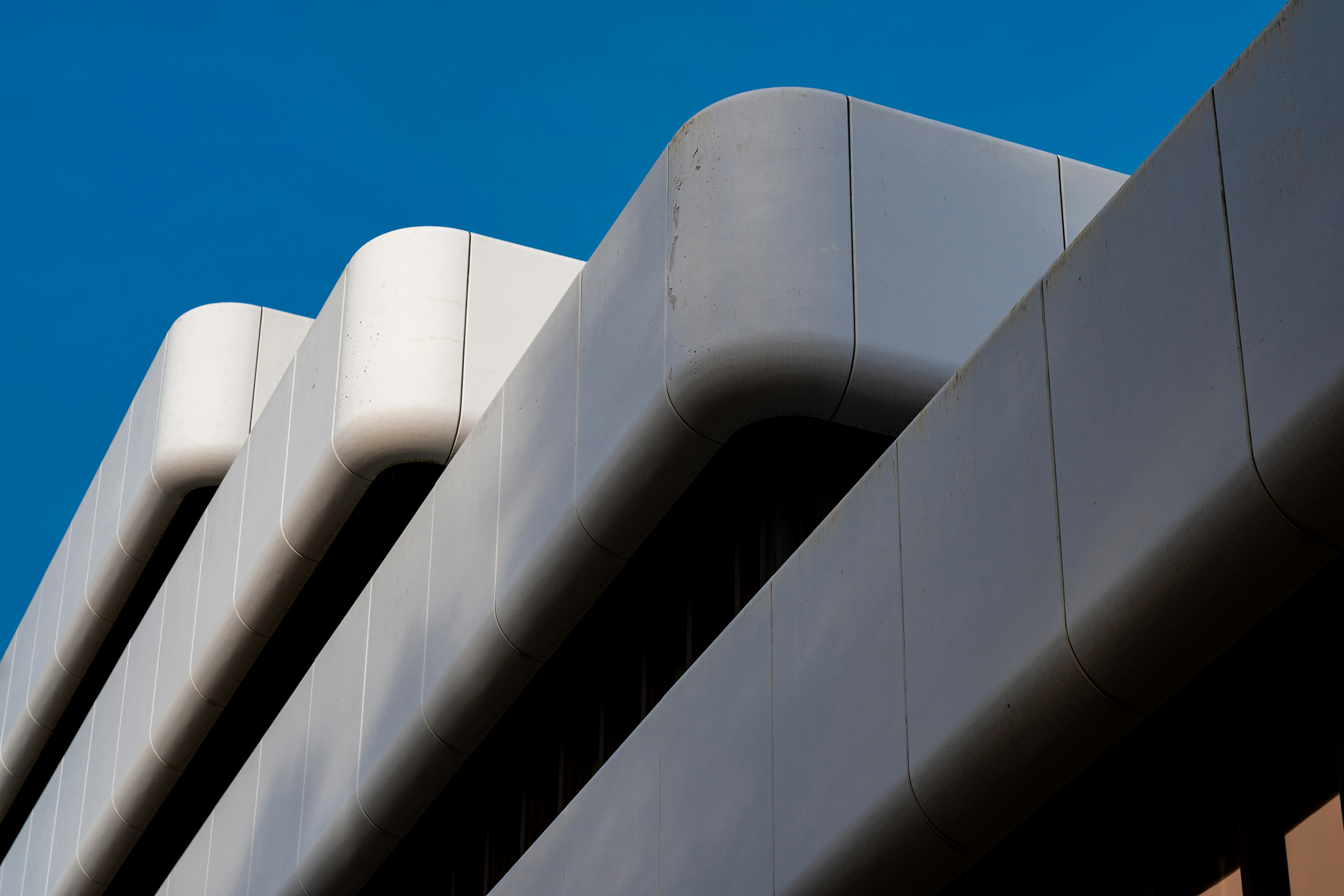 Modern architectural curves of a building set against a vivid blue sky.