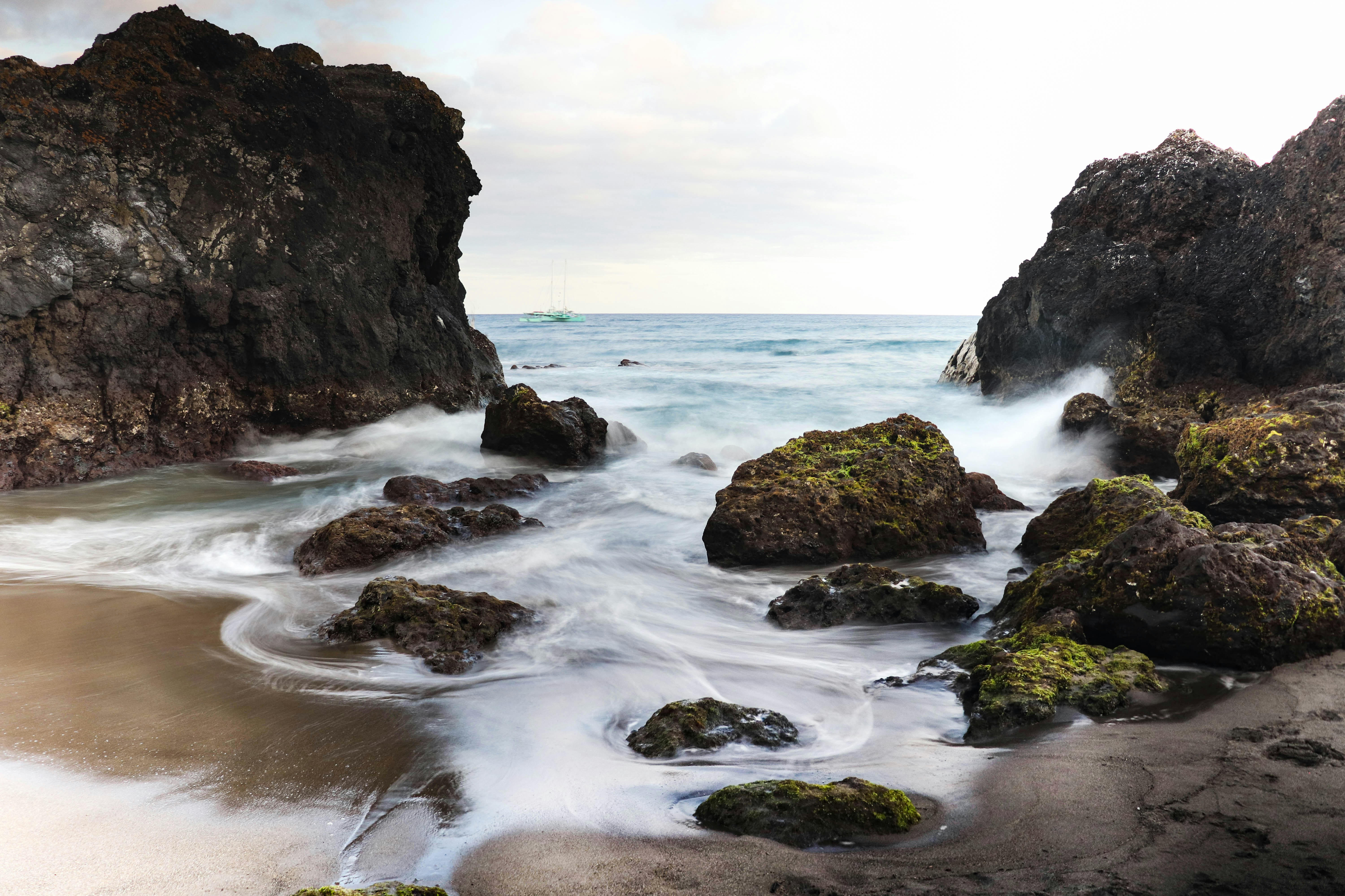 Foto zum Thema Ein felsiger Strand mit Wellen, die in und aus den ...