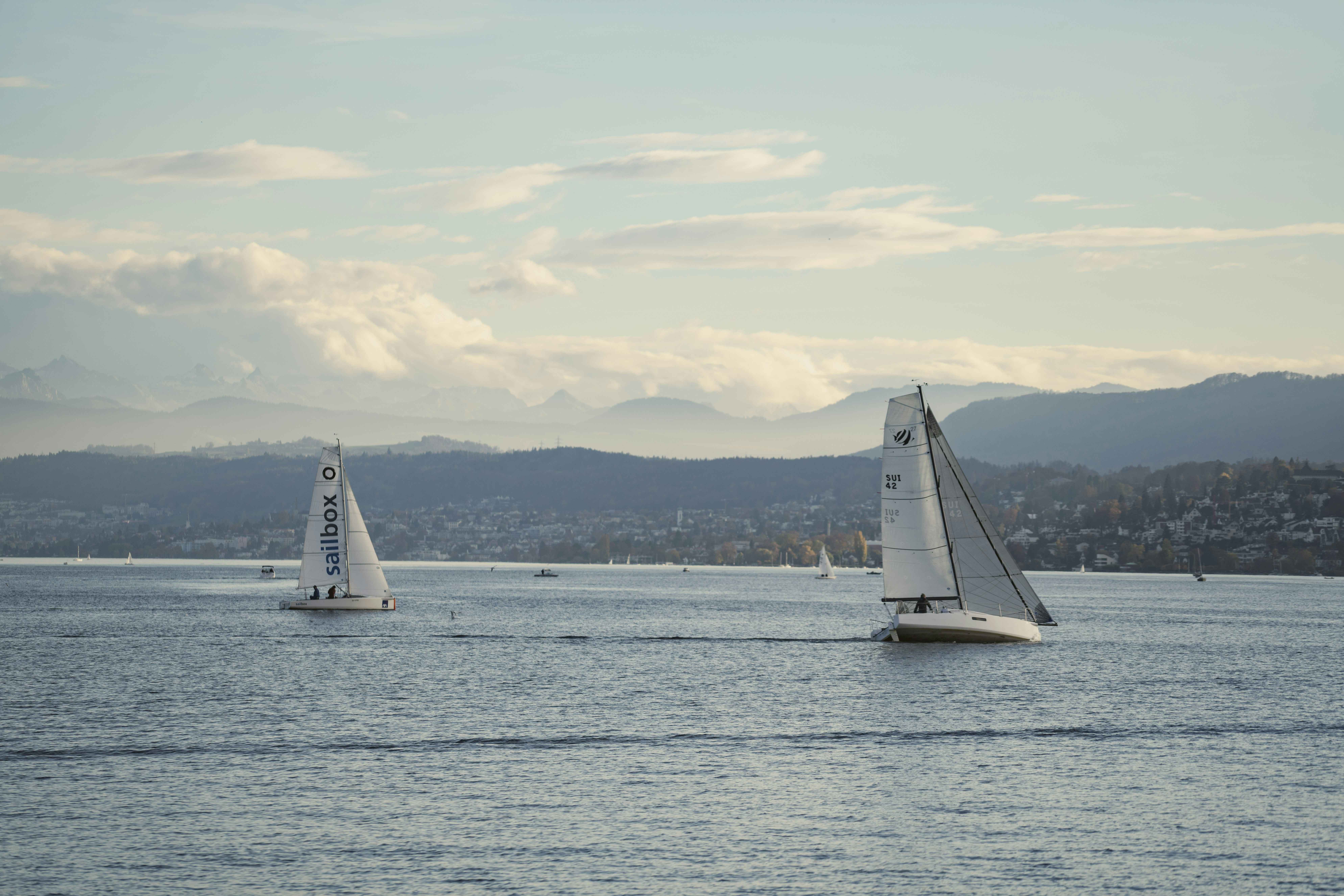 A couple of sail boats floating on top of a lake photo – Free ...