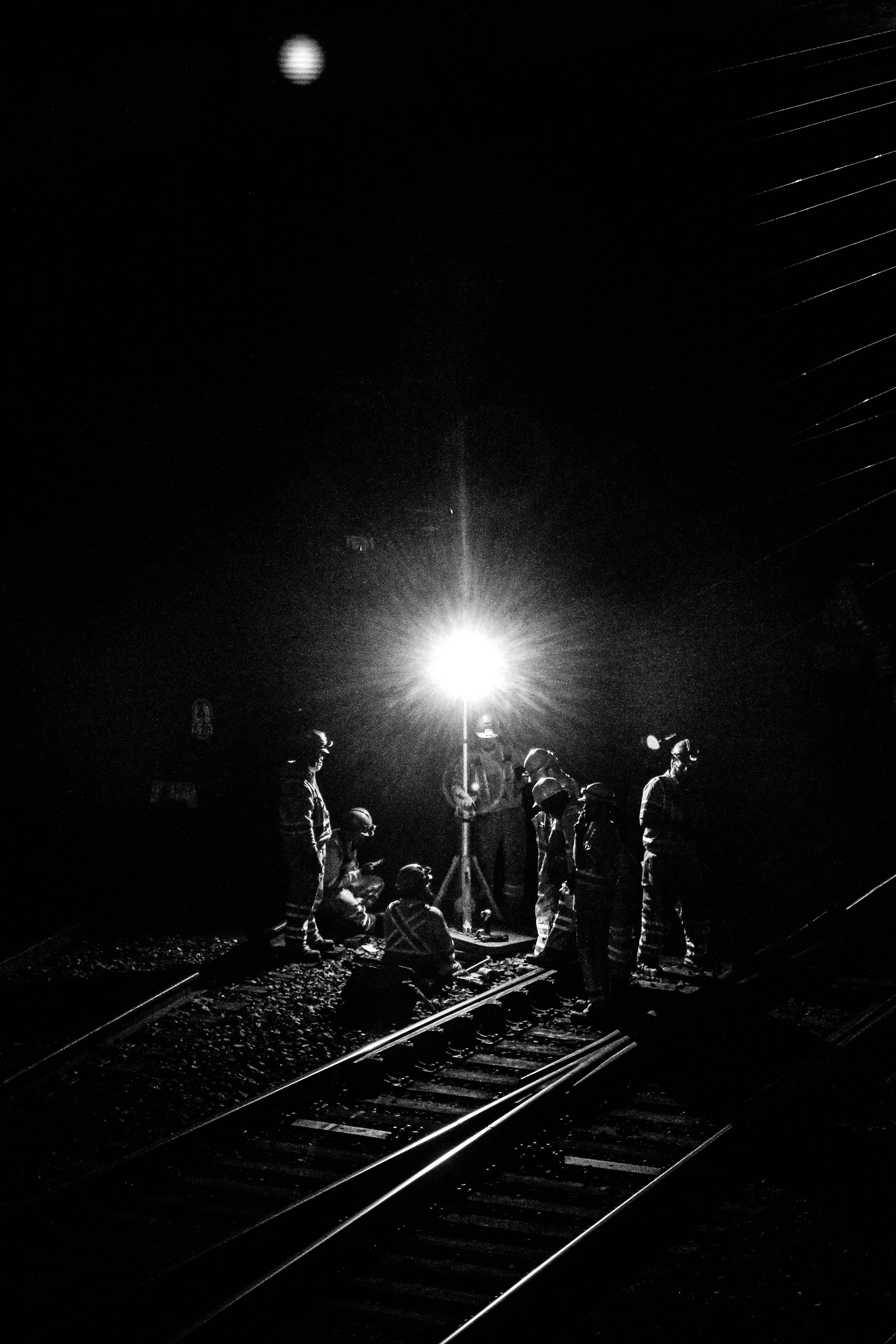 A group of people standing on a train track at night photo – Free ...