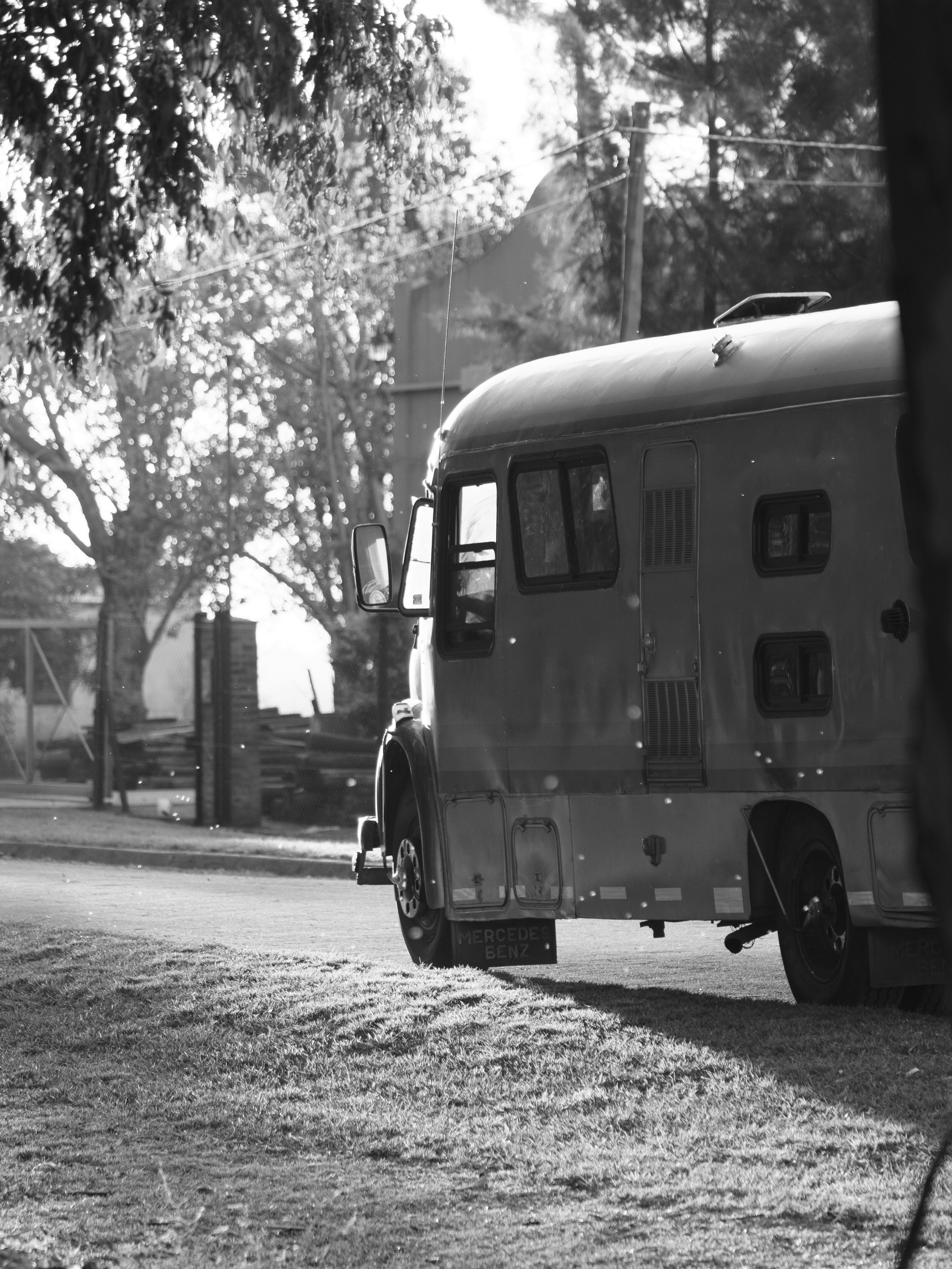 Vintage caravan parked along a tree-lined street, bathed in soft afternoon light. The scene evokes a sense of nostalgia and tranquility.