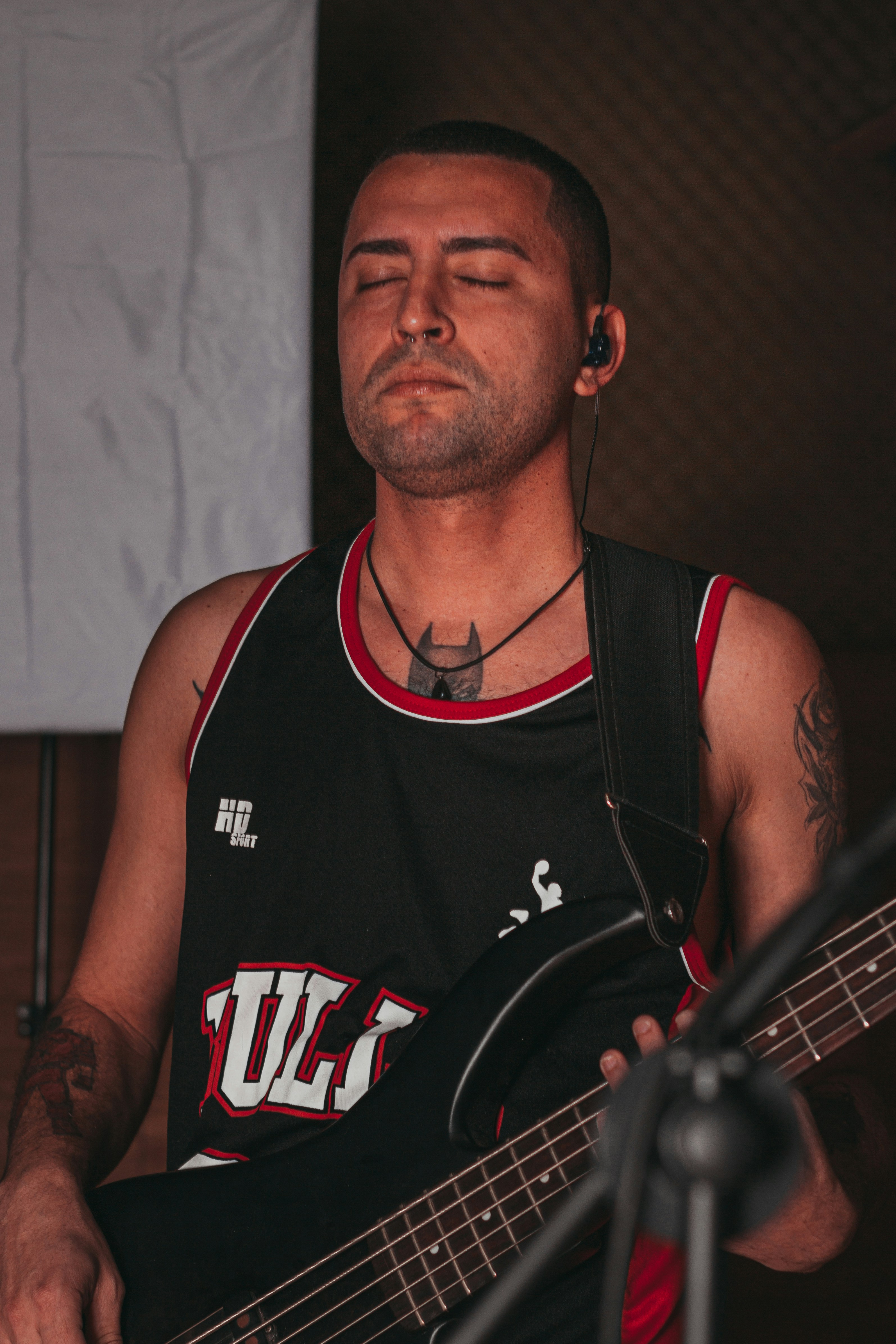 Bassist immersed in music, eyes closed, playing passionately in a studio setting. The focus is on the musician's expression and instrument.