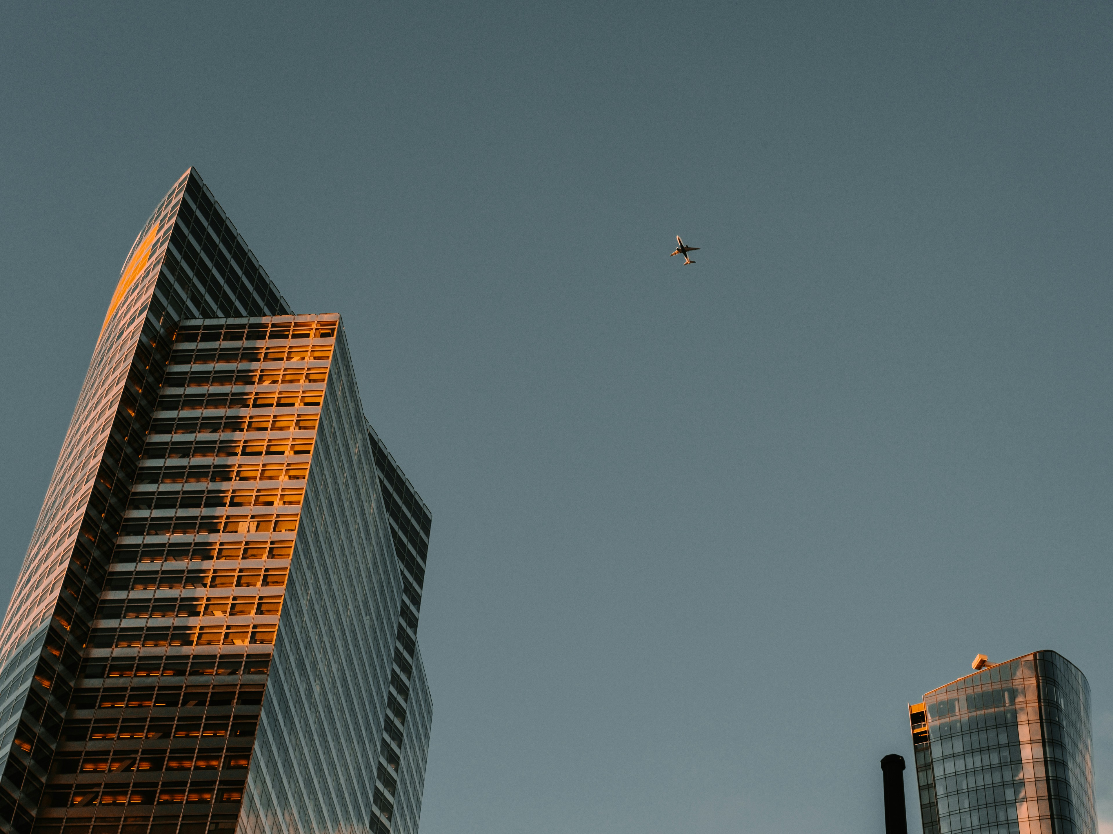 A plane flying in the sky between two tall buildings photo – Free ...