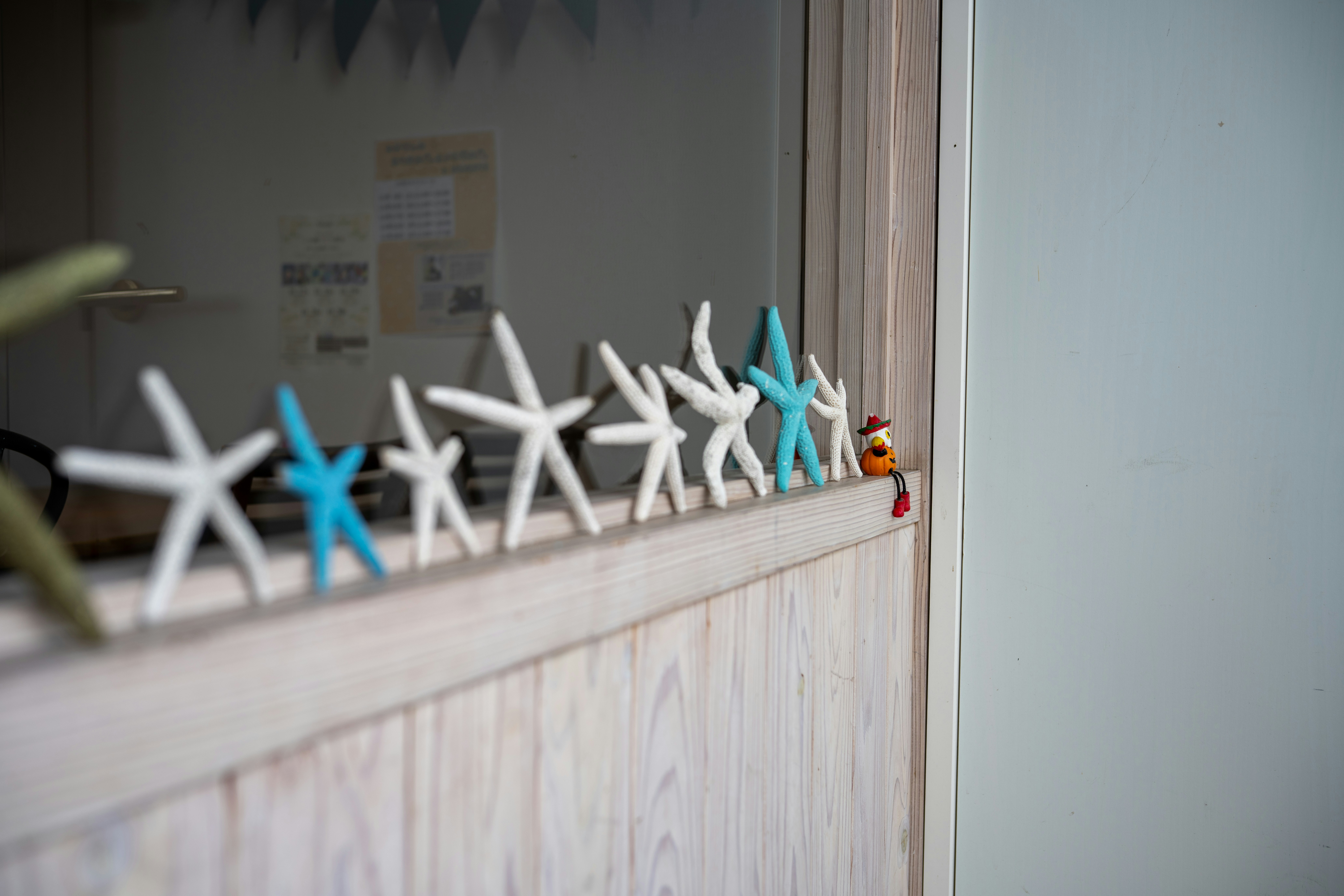 Row of Starfish on a Window Sill with a Tiny Orange Figure