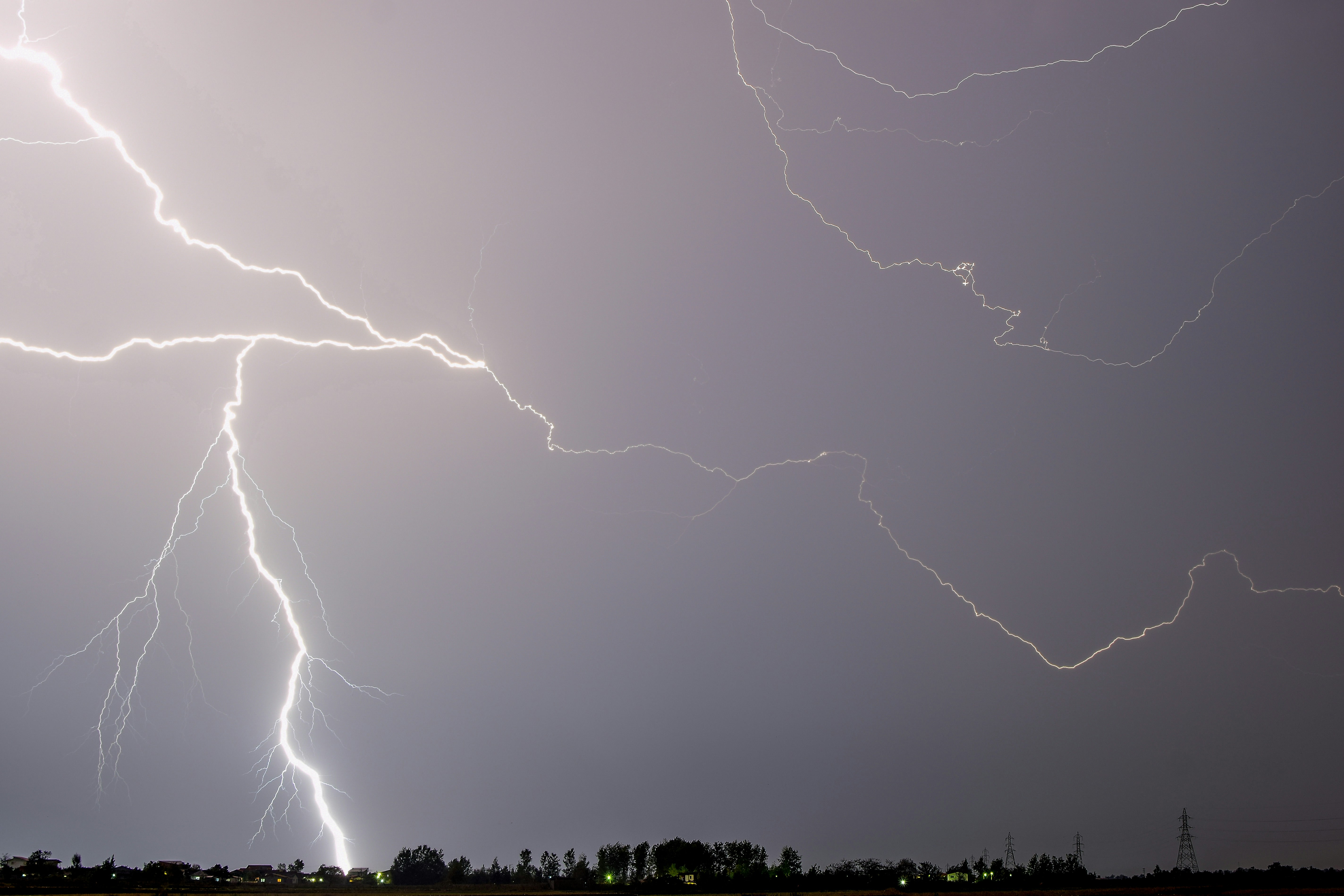 Dramatic lightning strikes illuminate the night sky over a distant landscape, showcasing nature's raw power and energy.