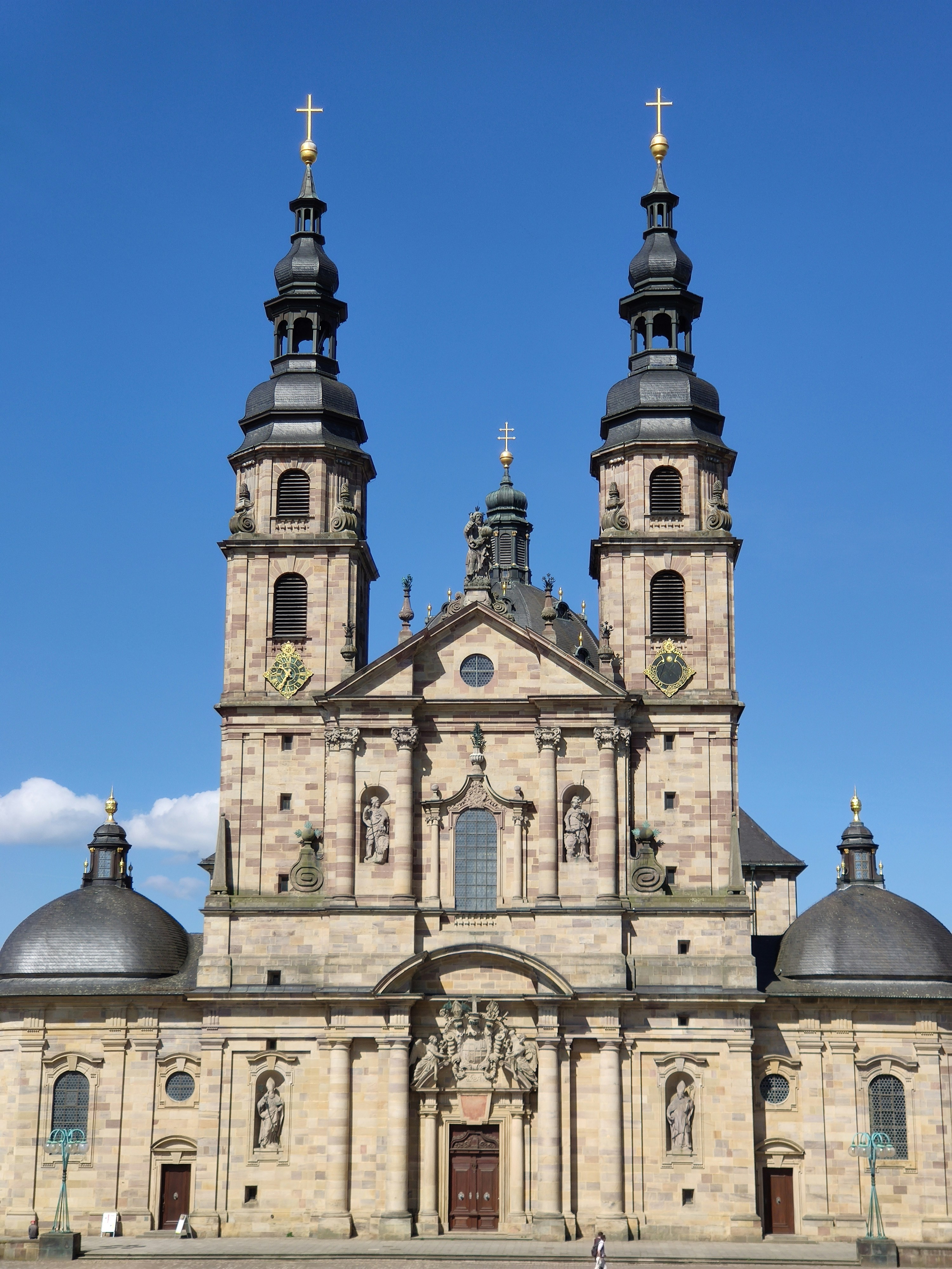 Stone cathedral facade with twin towers stands against a clear blue sky.