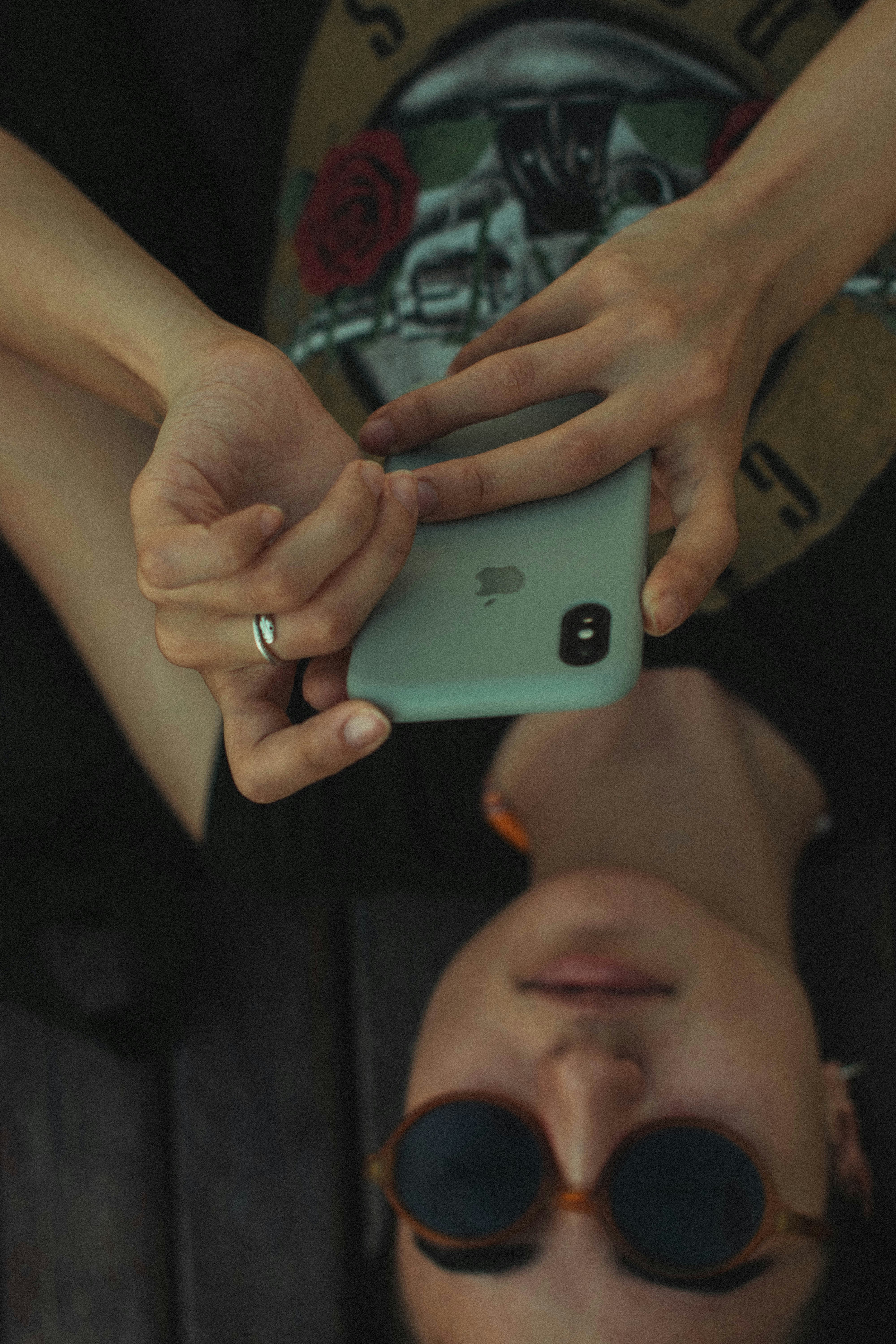 A person lounging with sunglasses, intently focused on their smartphone, surrounded by a relaxed atmosphere.