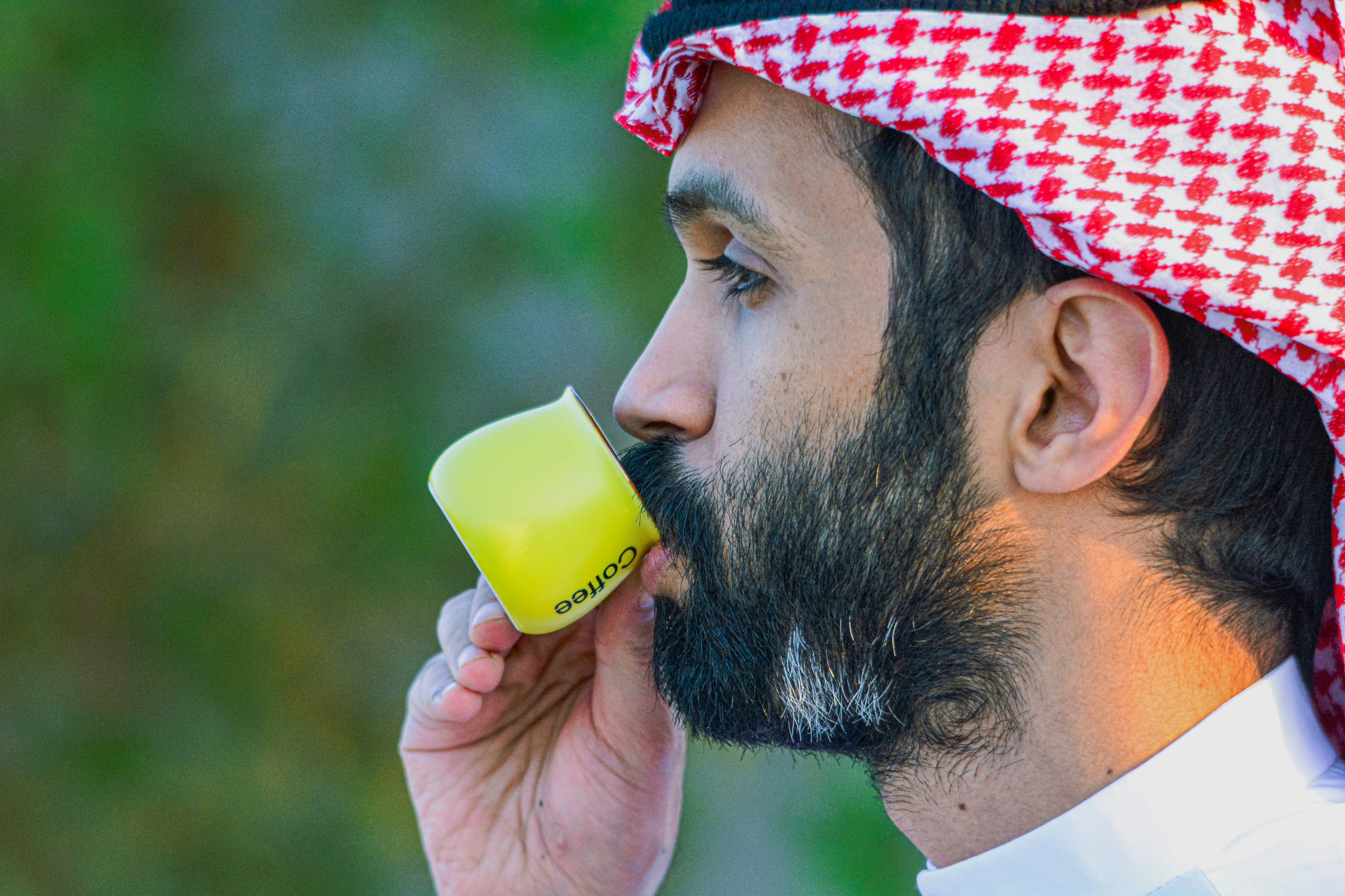 A man wearing a red and white checkered hat and holding a yellow cup ...