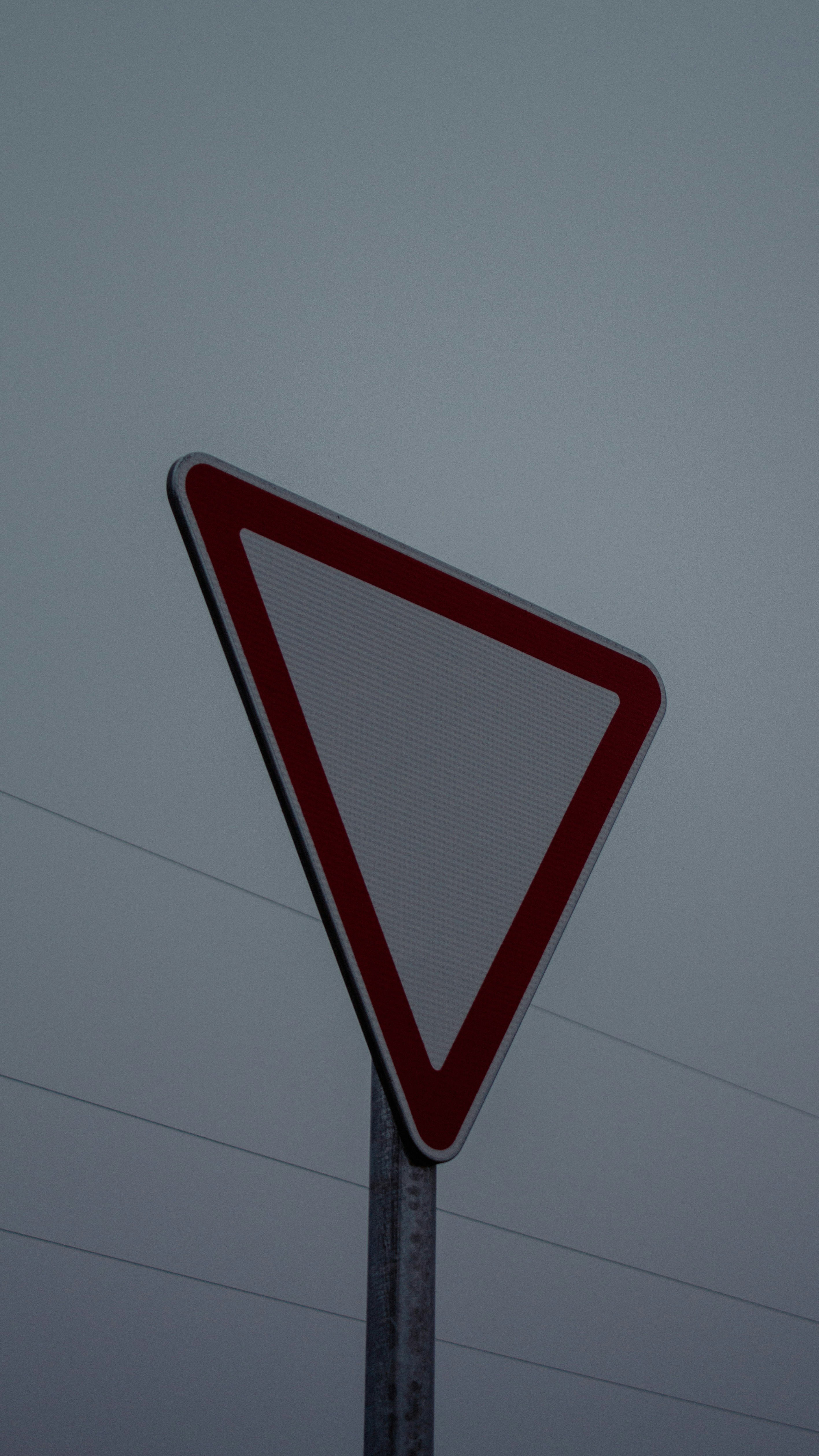 A red and white triangular sign sitting on top of a metal pole photo ...