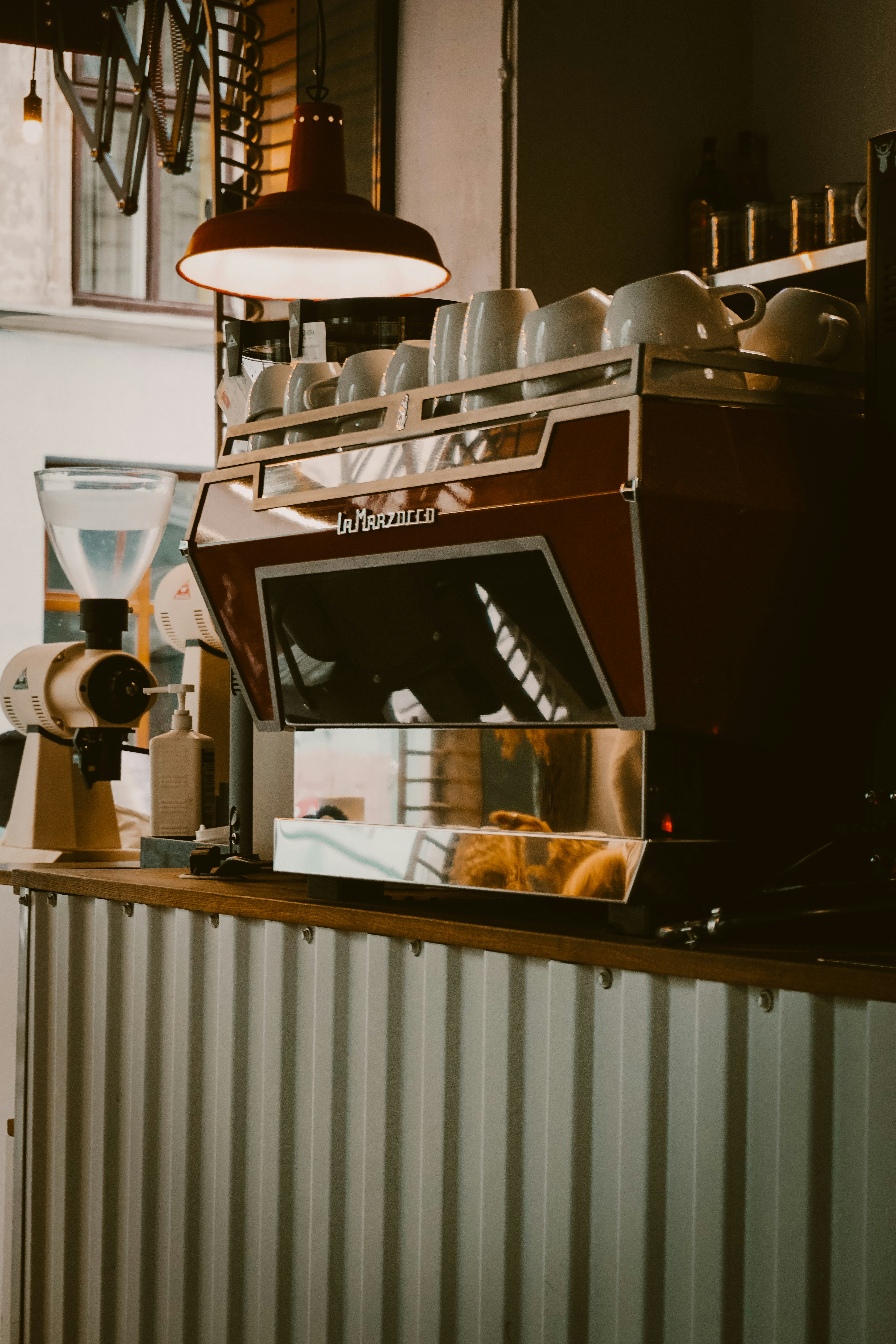 A La Marzocco espresso machine stands prominently on a café counter, surrounded by coffee cups and brewing equipment.