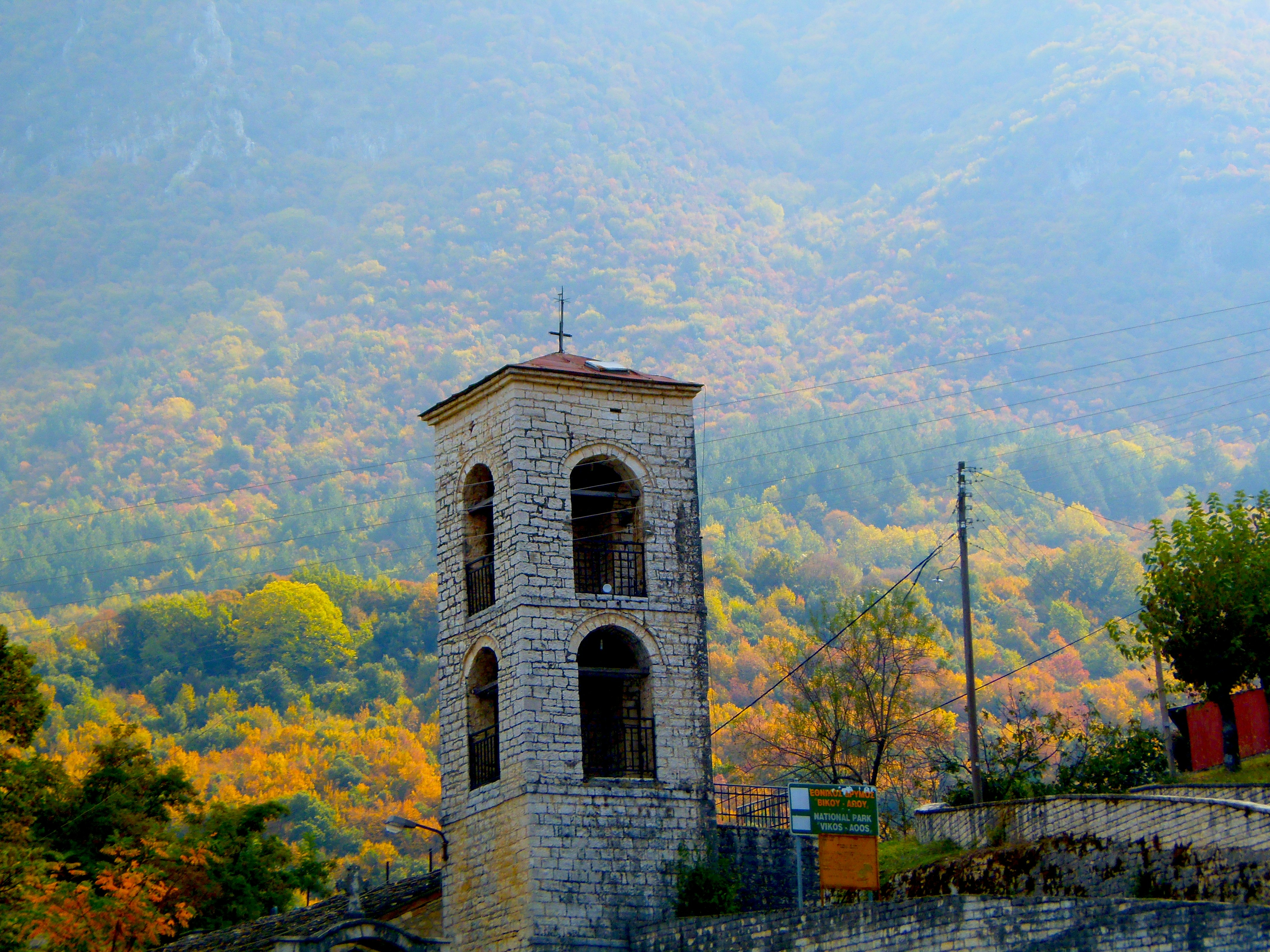 A historic stone bell tower stands against a backdrop of vibrant autumn foliage, showcasing the interplay of architecture and nature.