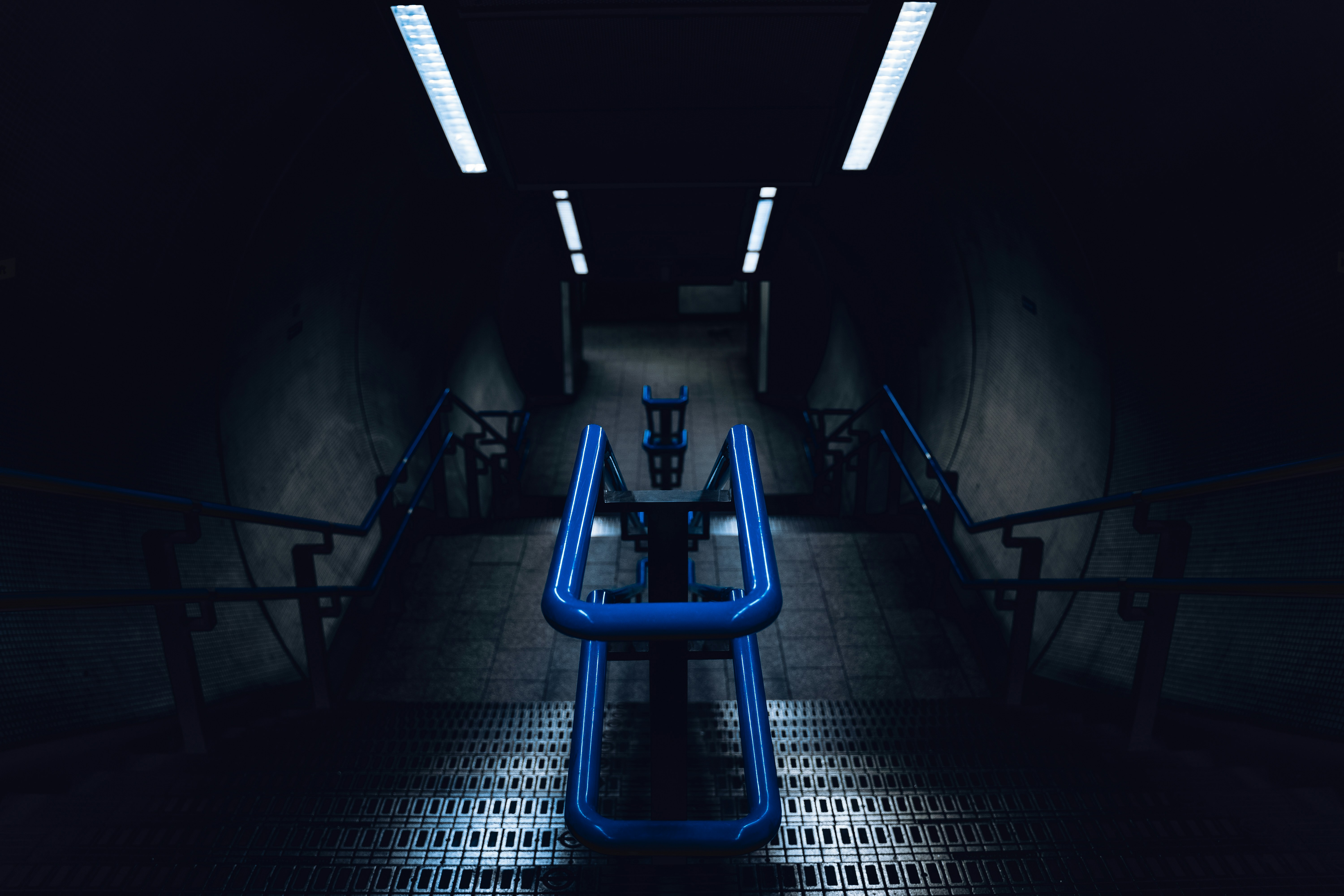 Symmetry in Blue: Neon Handrails Framing an Empty Underground Corridor