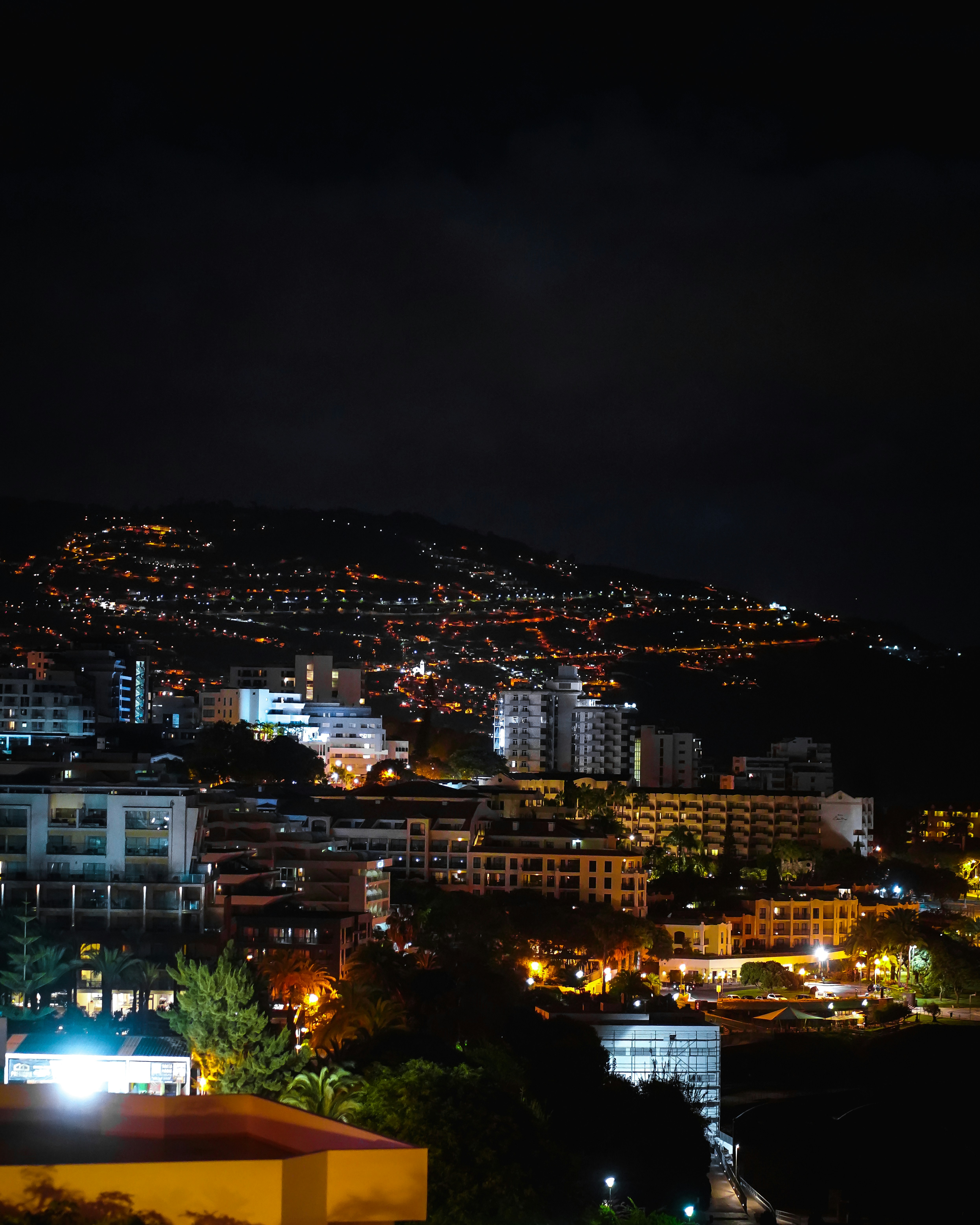 Night city photograph of hillside buildings lit by warm streetlights, tracing a glowing ridge across the dark sky.