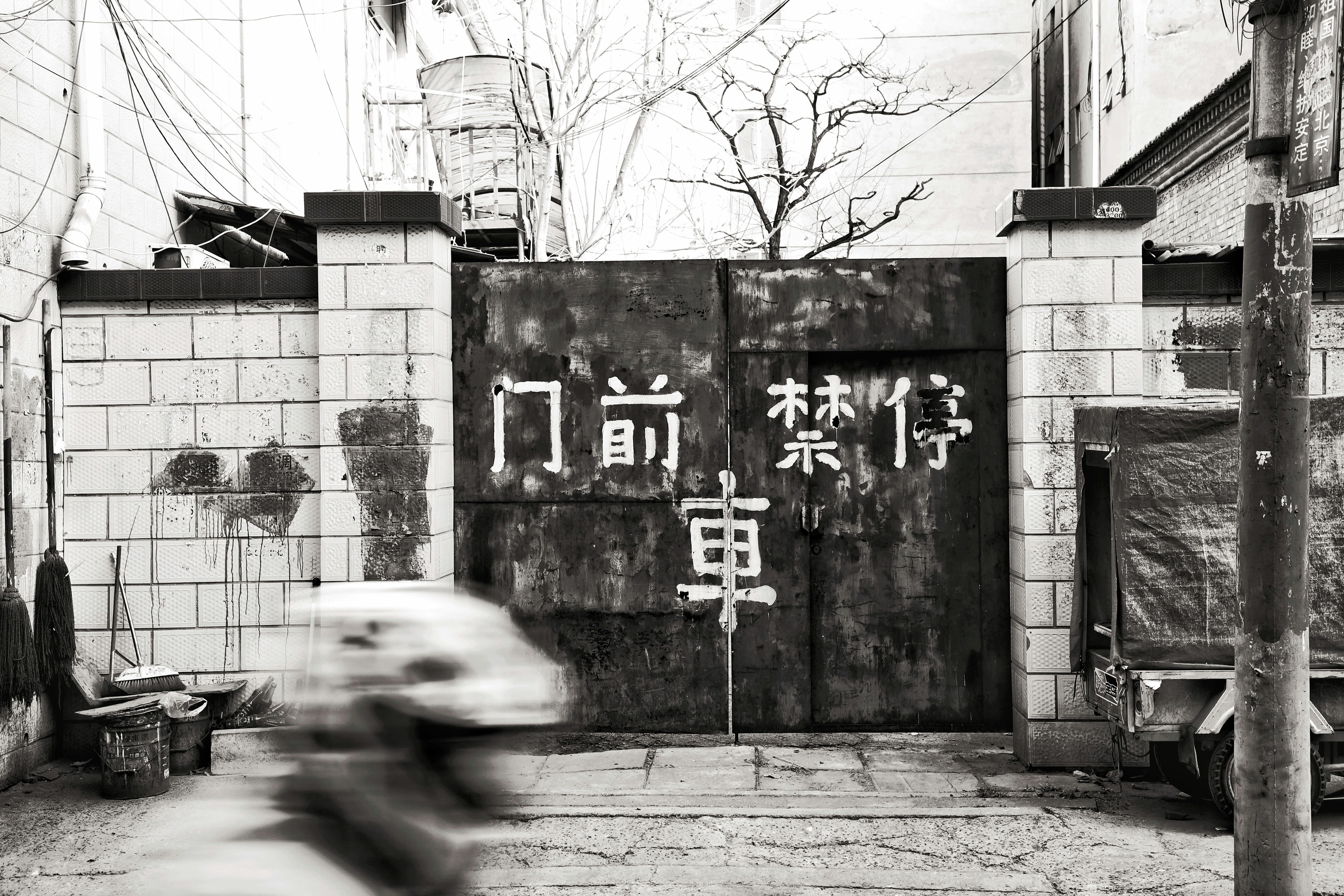 A motorcyclist rides past a gate with chinese writing on it photo ...