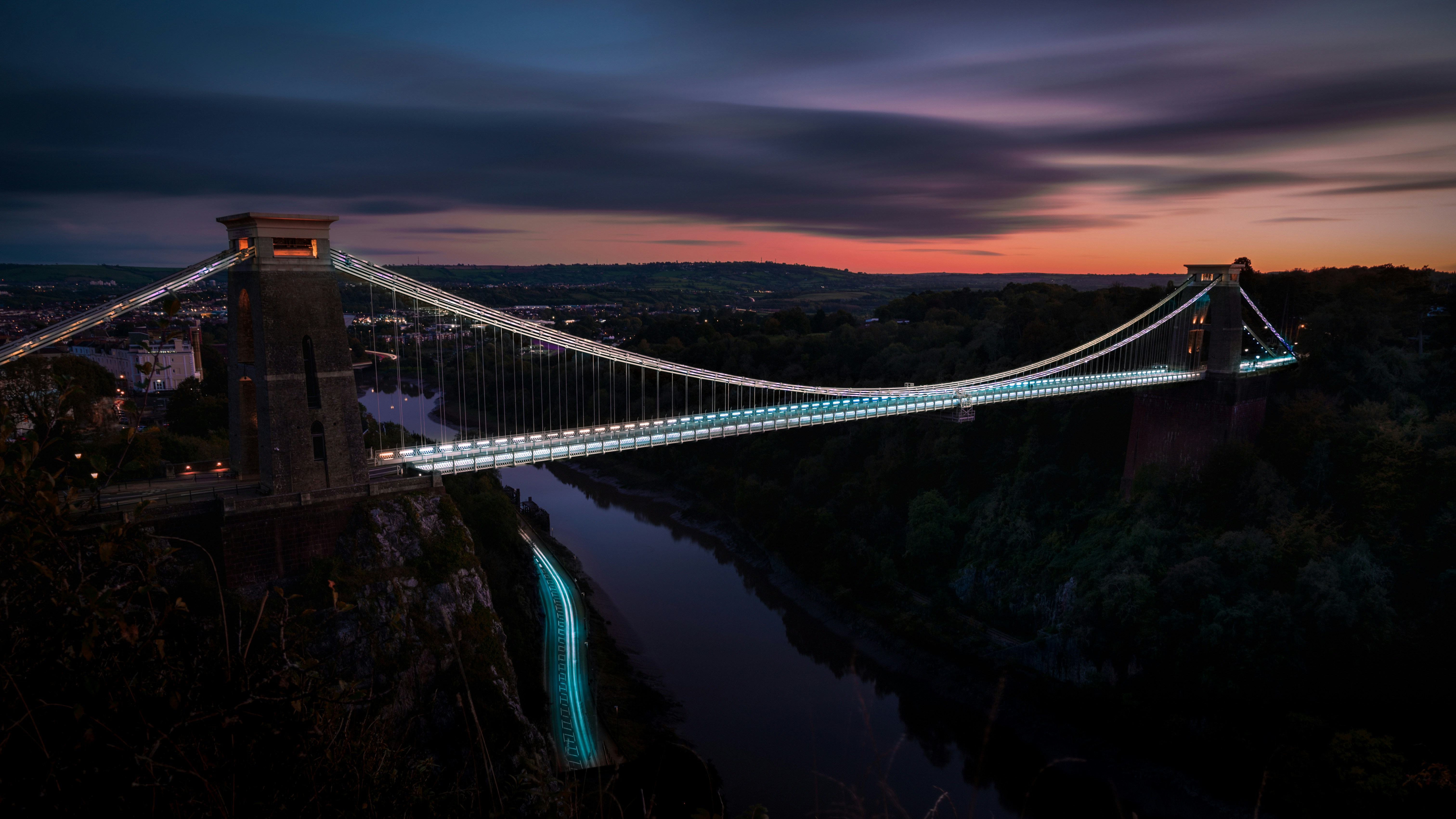 Nocturnal Arc: Illuminated Suspension Bridge Over a Quiet River