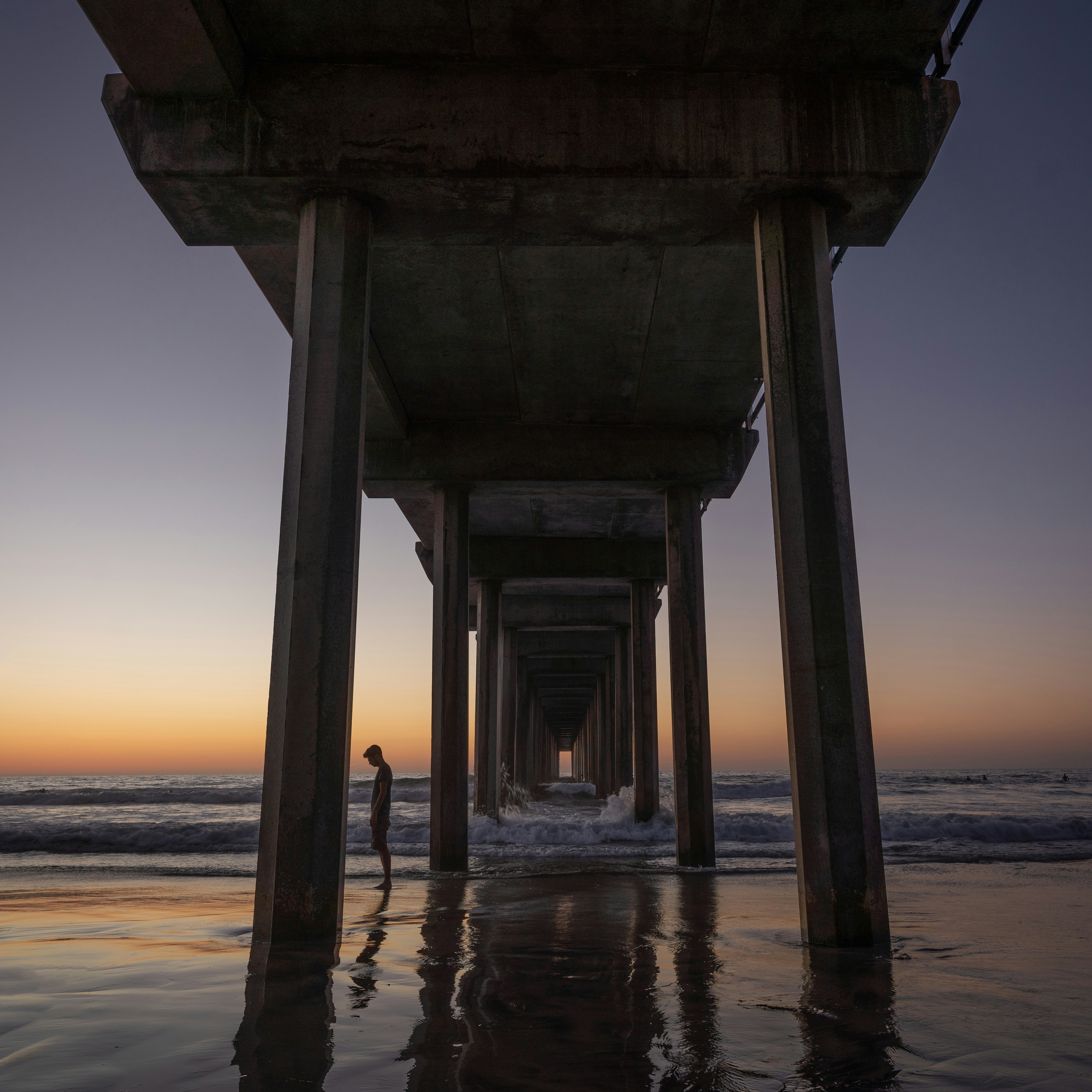 A person standing under a pier at sunset photo – Free Adventure Image ...