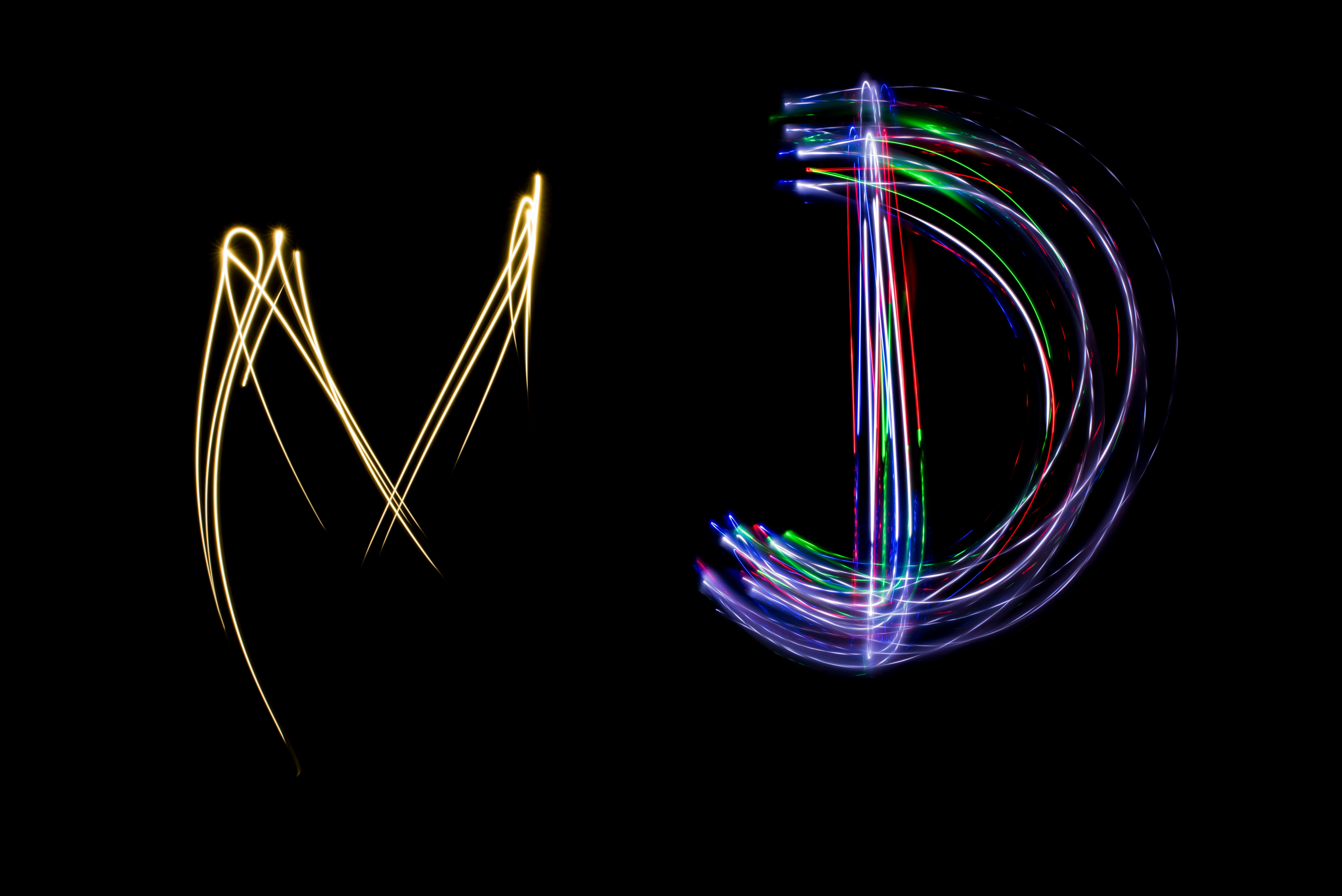 Light trails forming the letters M and D against a black background, showcasing a dynamic display of color and motion.