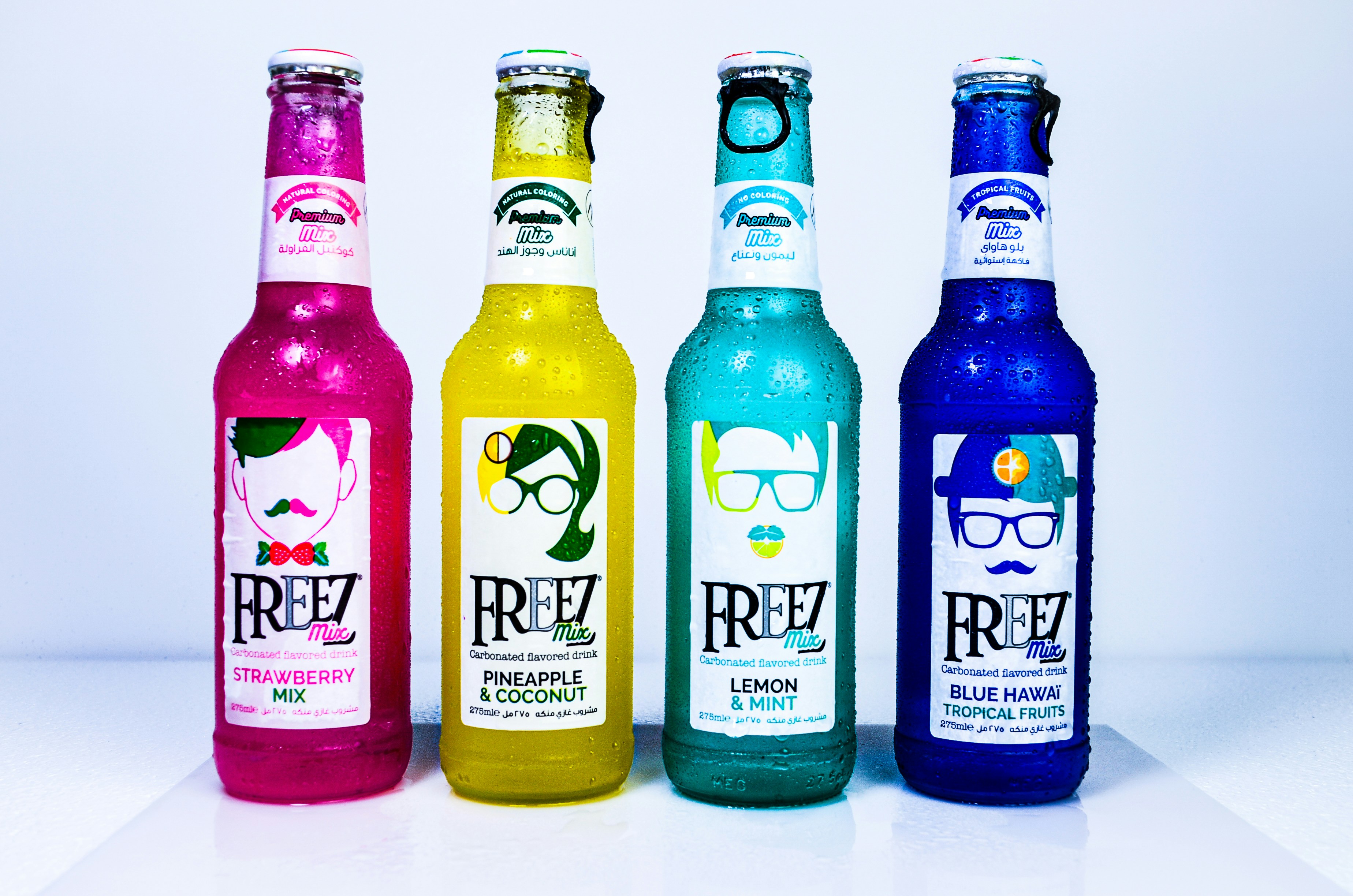 A group of four bottles of soda sitting next to each other photo – Free ...