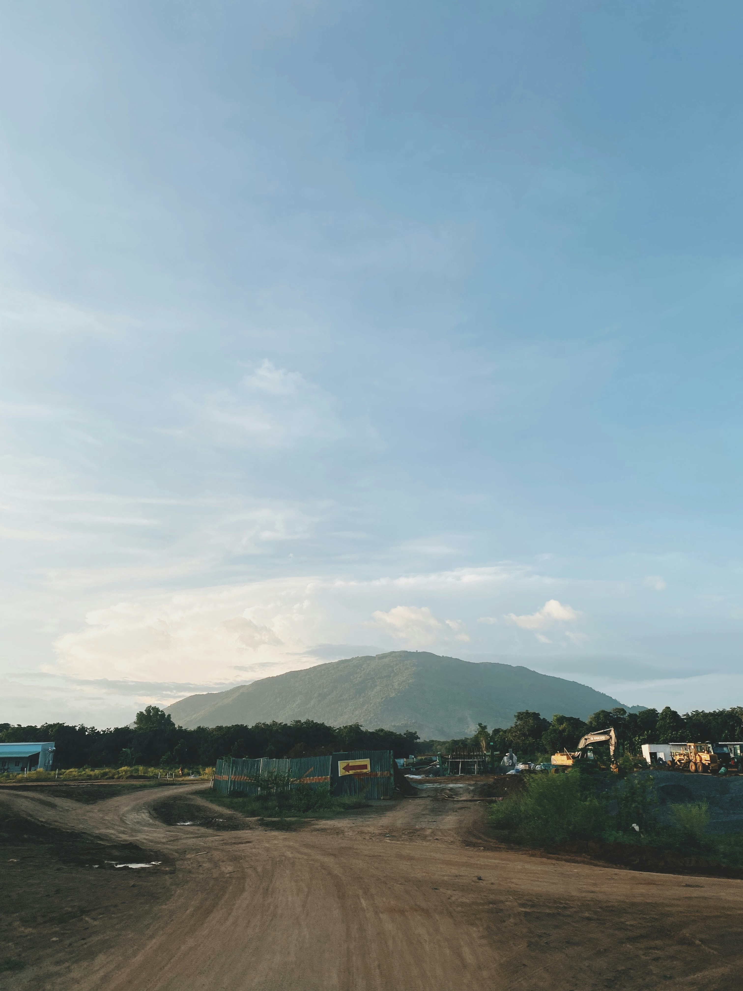 Dusty road toward a distant hill under a calm blue sky