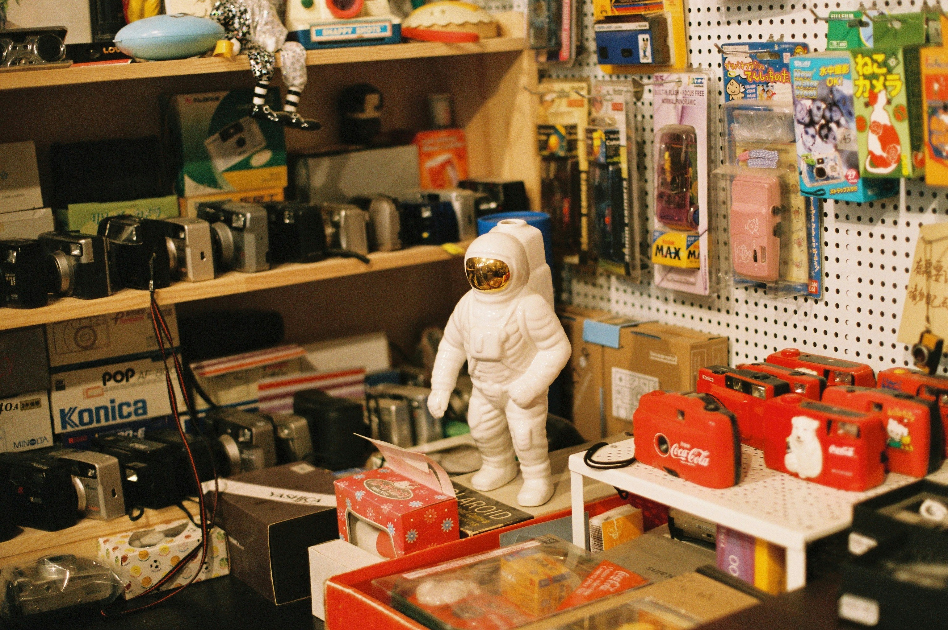White Astronaut Among Cameras: A Quiet Constellation in a Gadget Shop