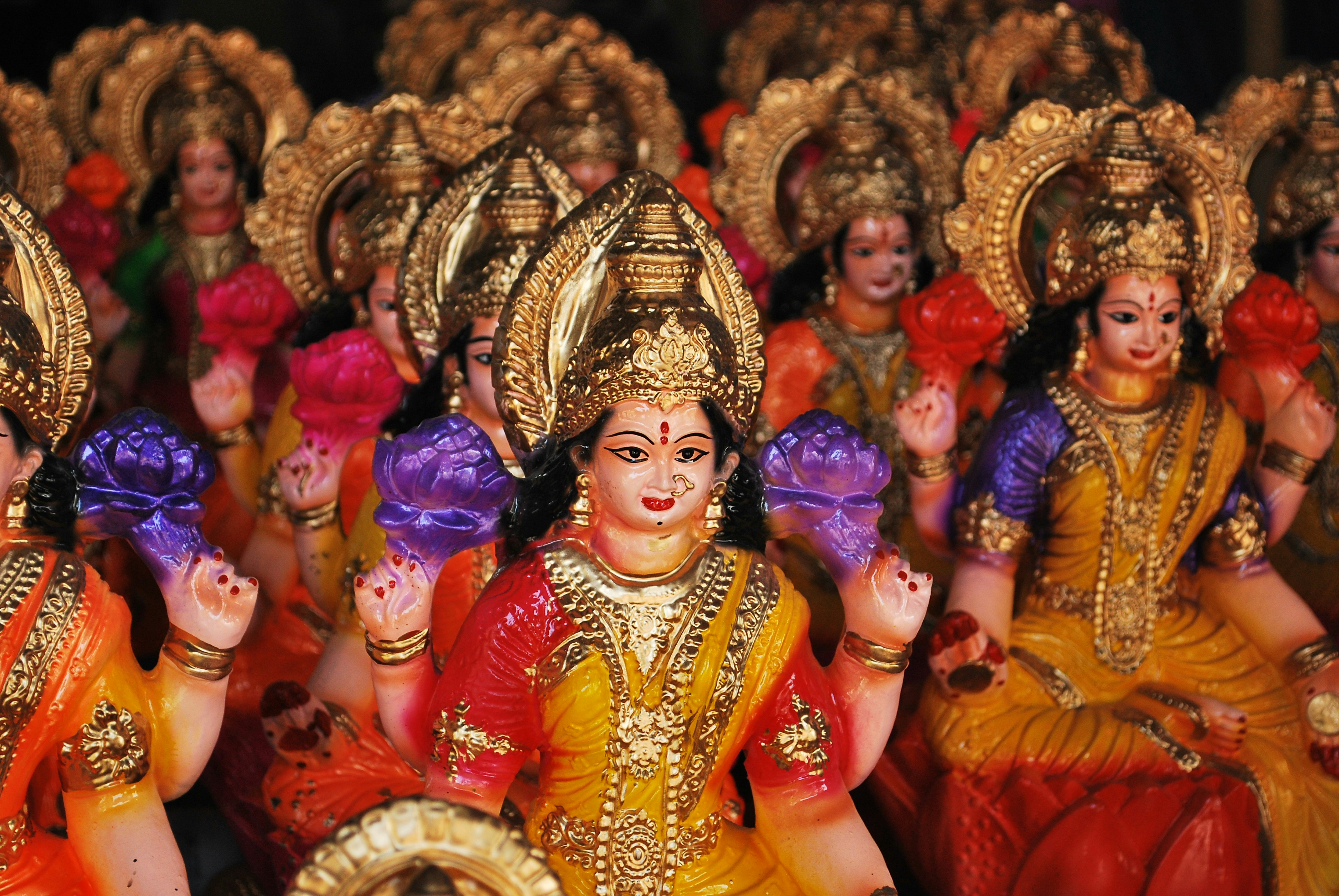 Vibrant array of intricately crafted goddess figurines, each adorned in colorful attire and holding symbolic objects. The display showcases the artistry of traditional craftsmanship.