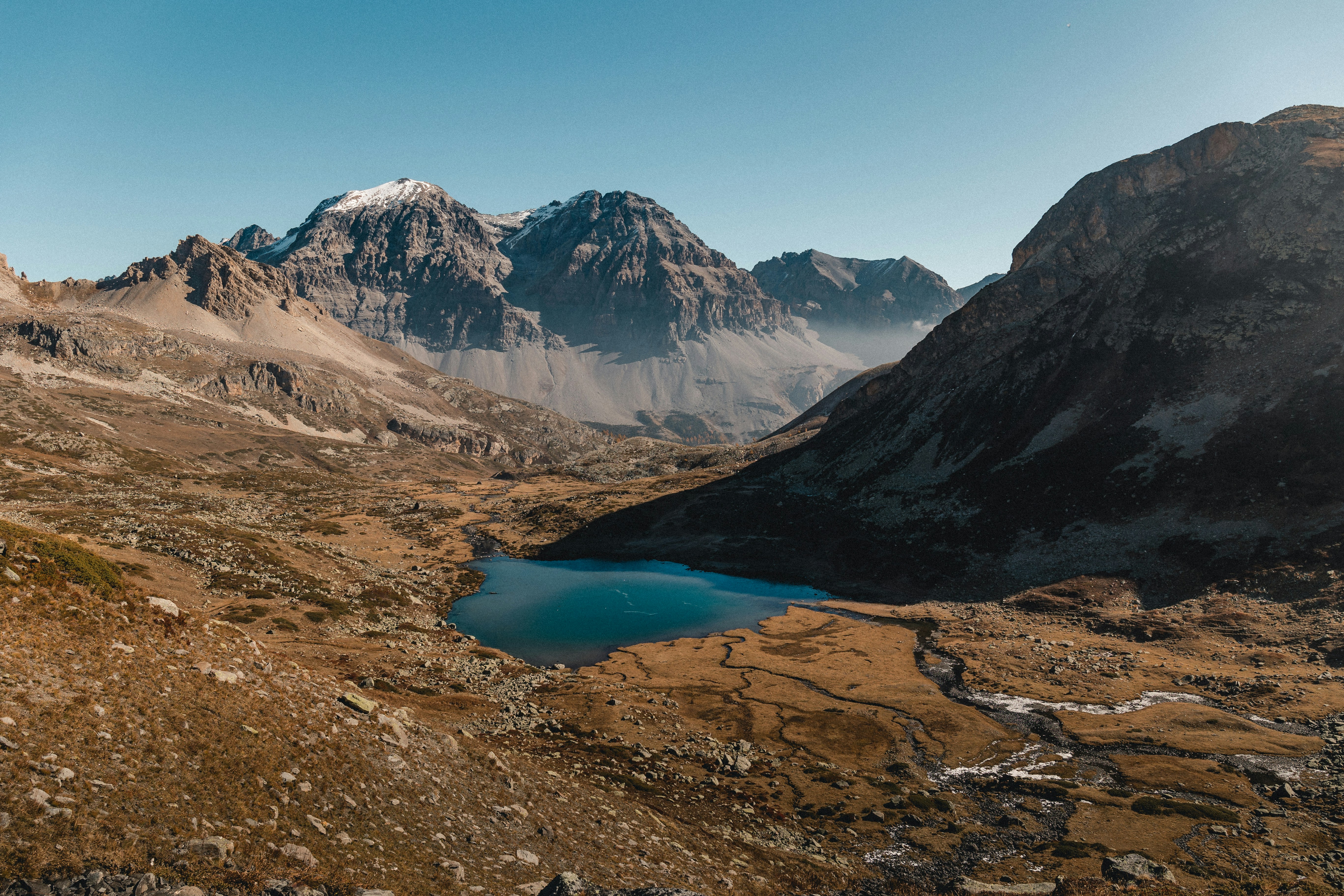 Mountain range encircling a serene blue lake under a clear sky.