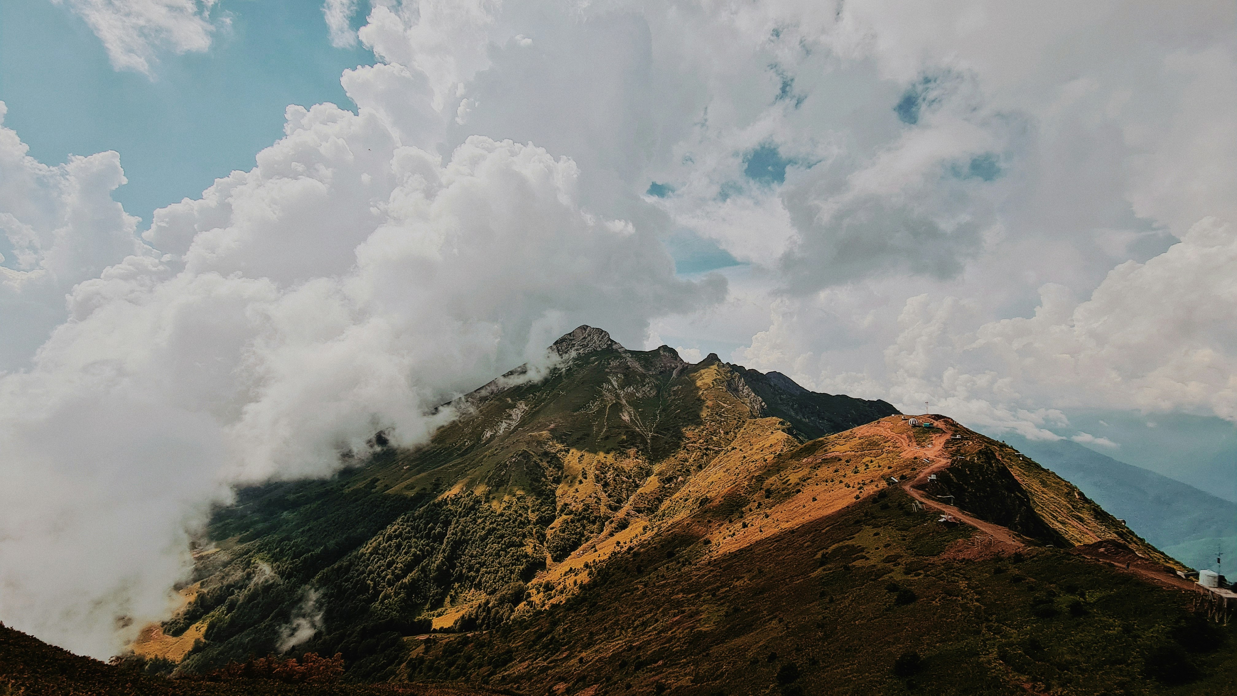 Mountain peak partially shrouded in clouds under a bright sky.