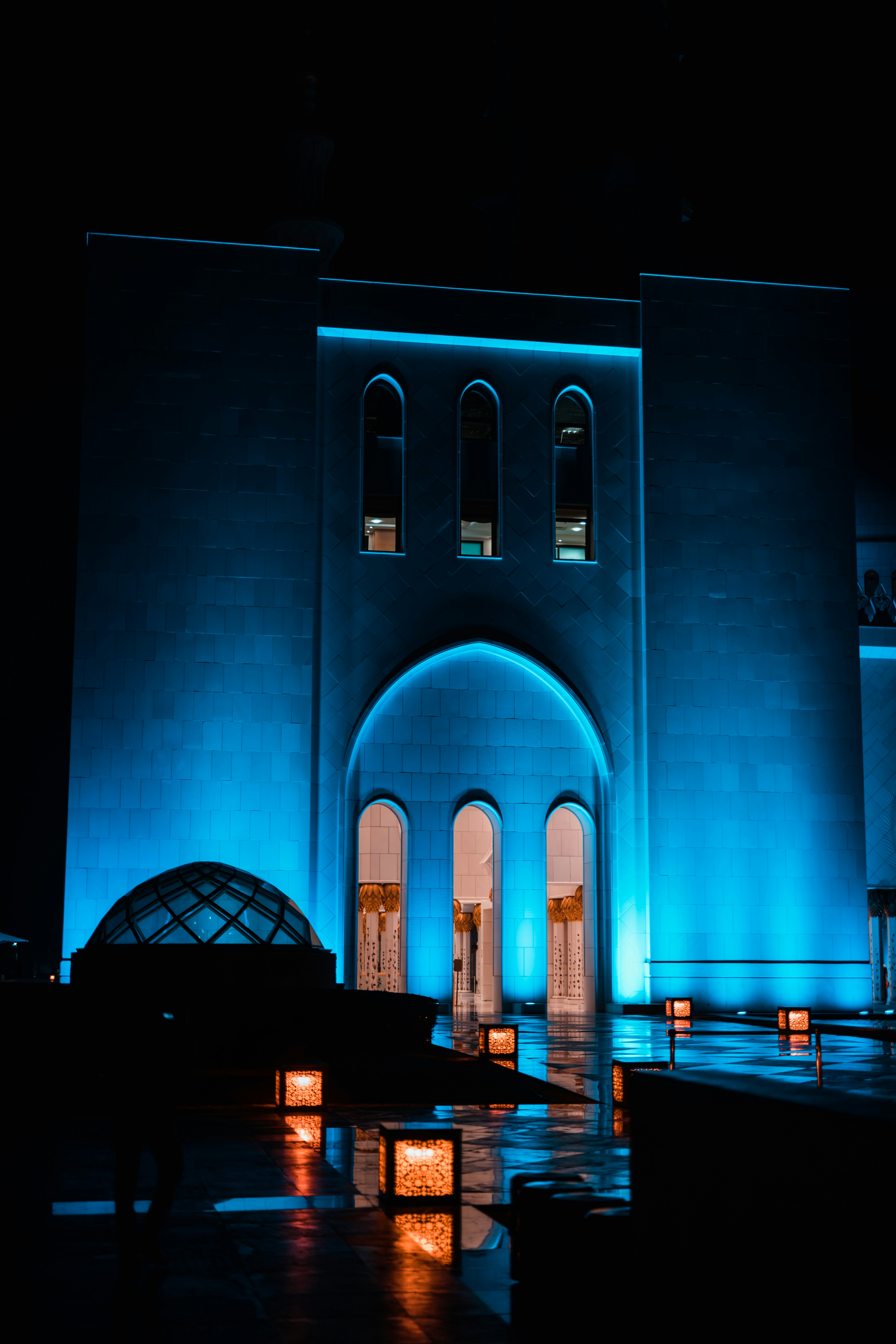 A building lit up with blue lights at night photo – Free City Image on ...
