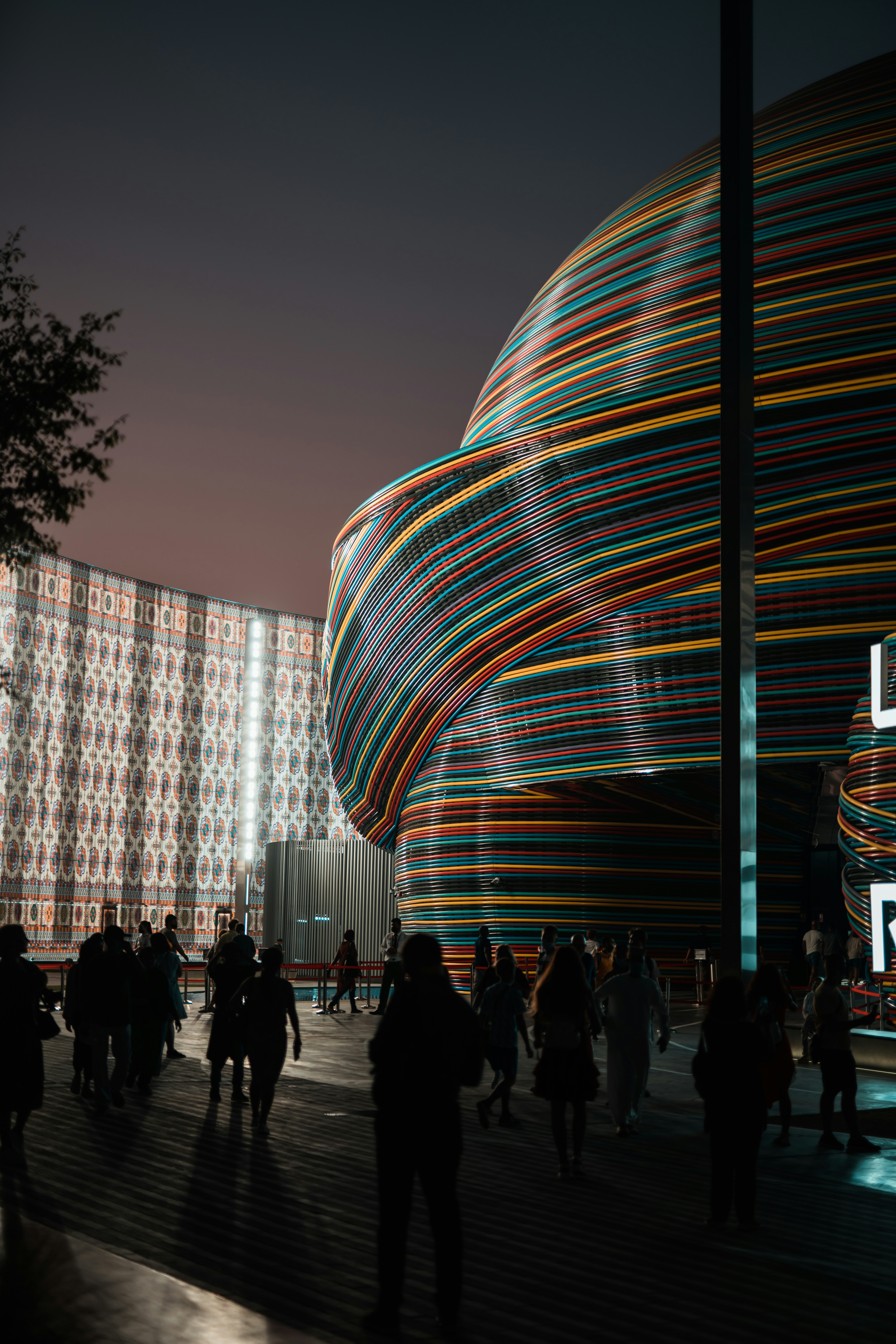 Twilight Ribbon Sphere: Neon Stripes Curving Over a Nighttime Crowd