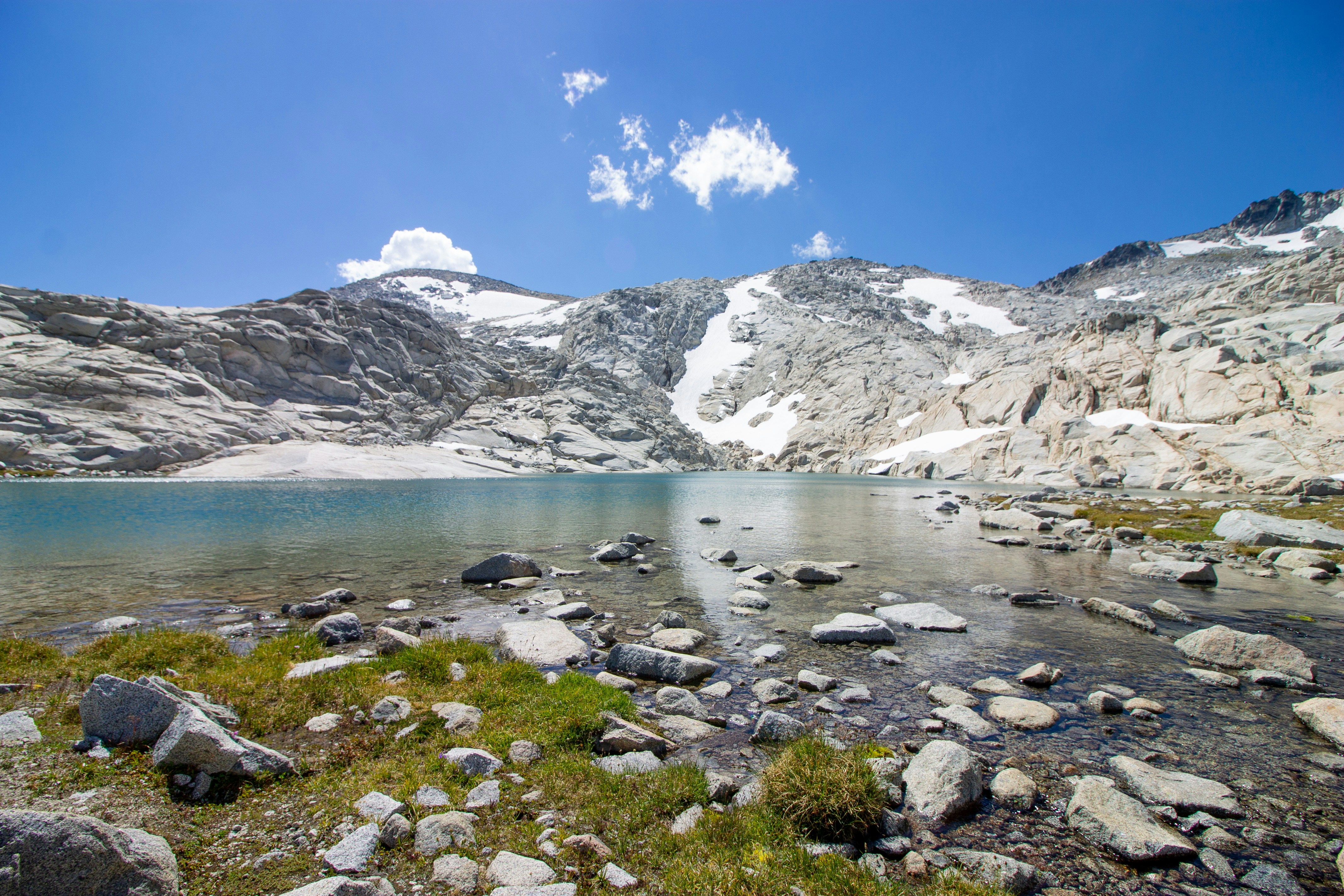 Un lac de montagne entouré de rochers et d’herbe photo – Photo La ...