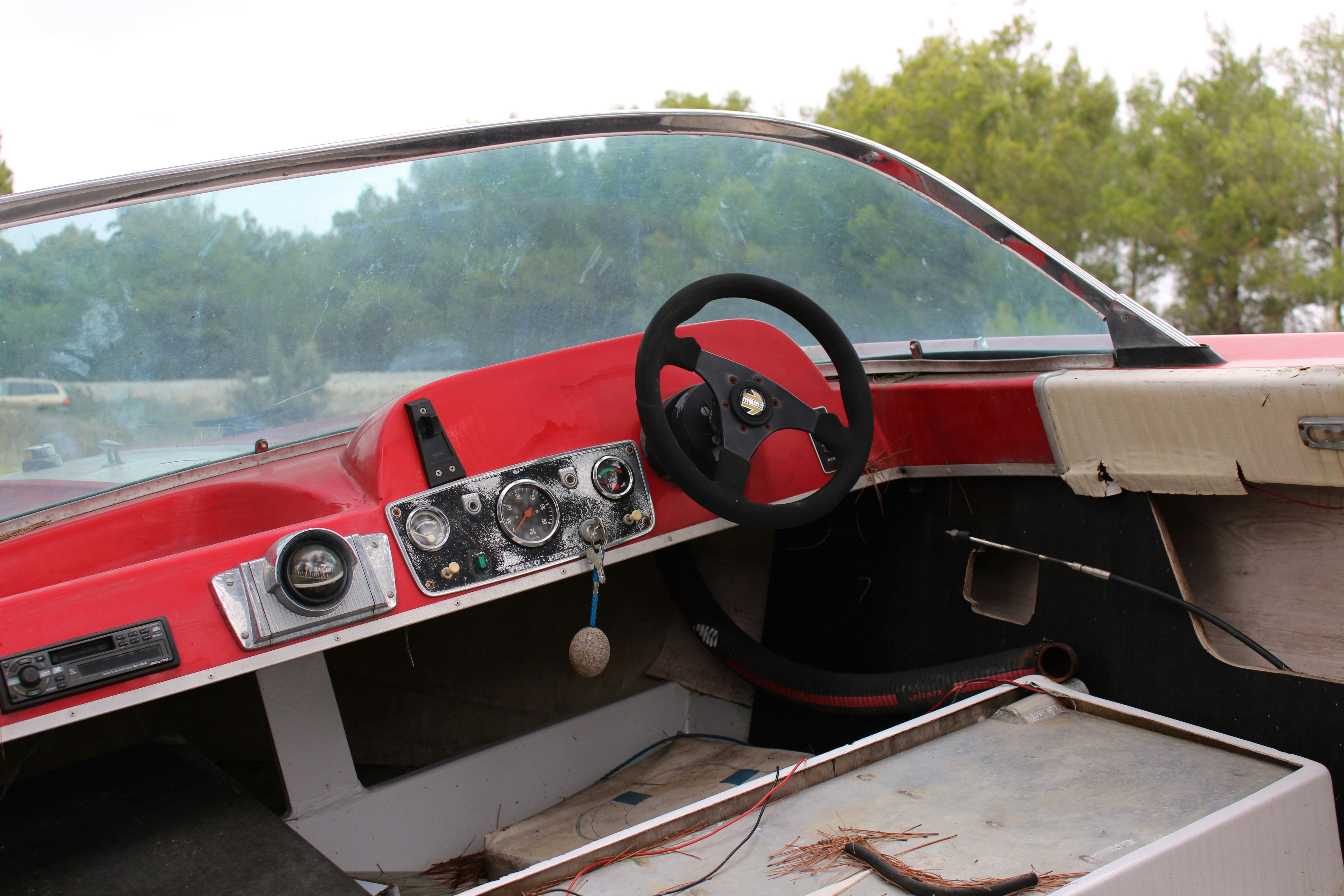 Red cockpit relic: vintage boat dashboard and steering wheel