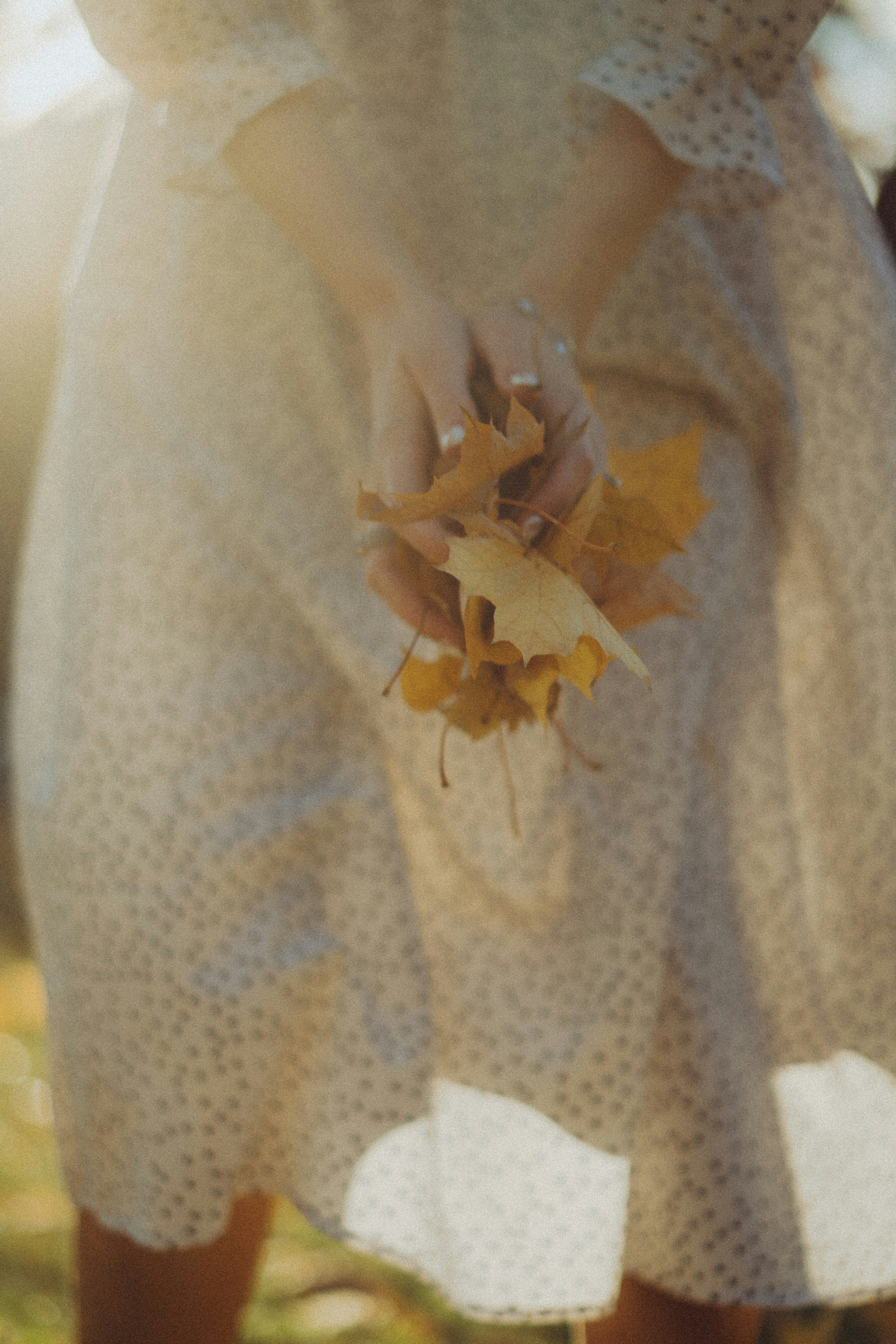 a woman in a dress holding a bunch of leaves