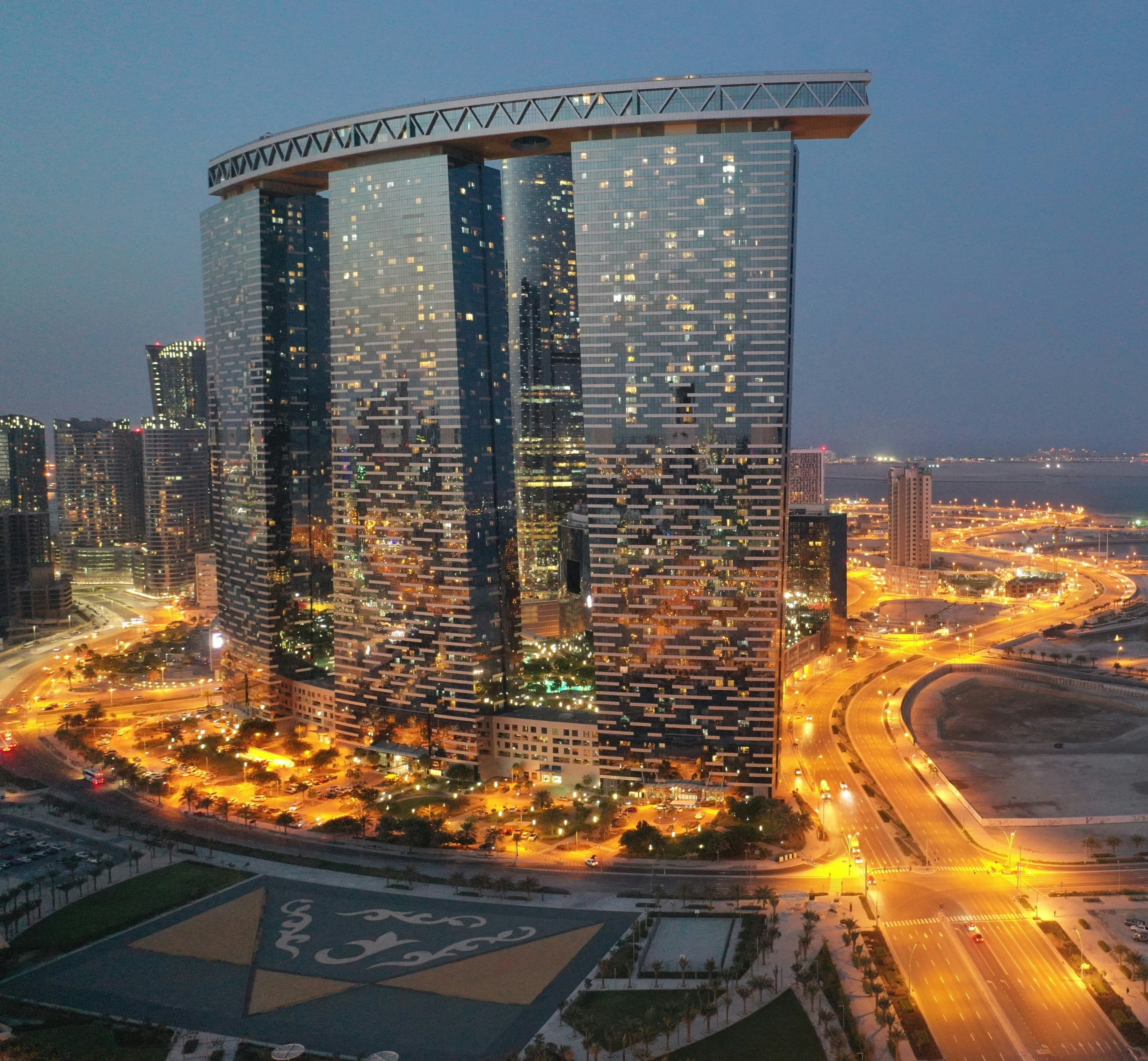 Dramatic view of the Gate Towers on Al Reem Island as city lights illuminate the dusk skyline.
