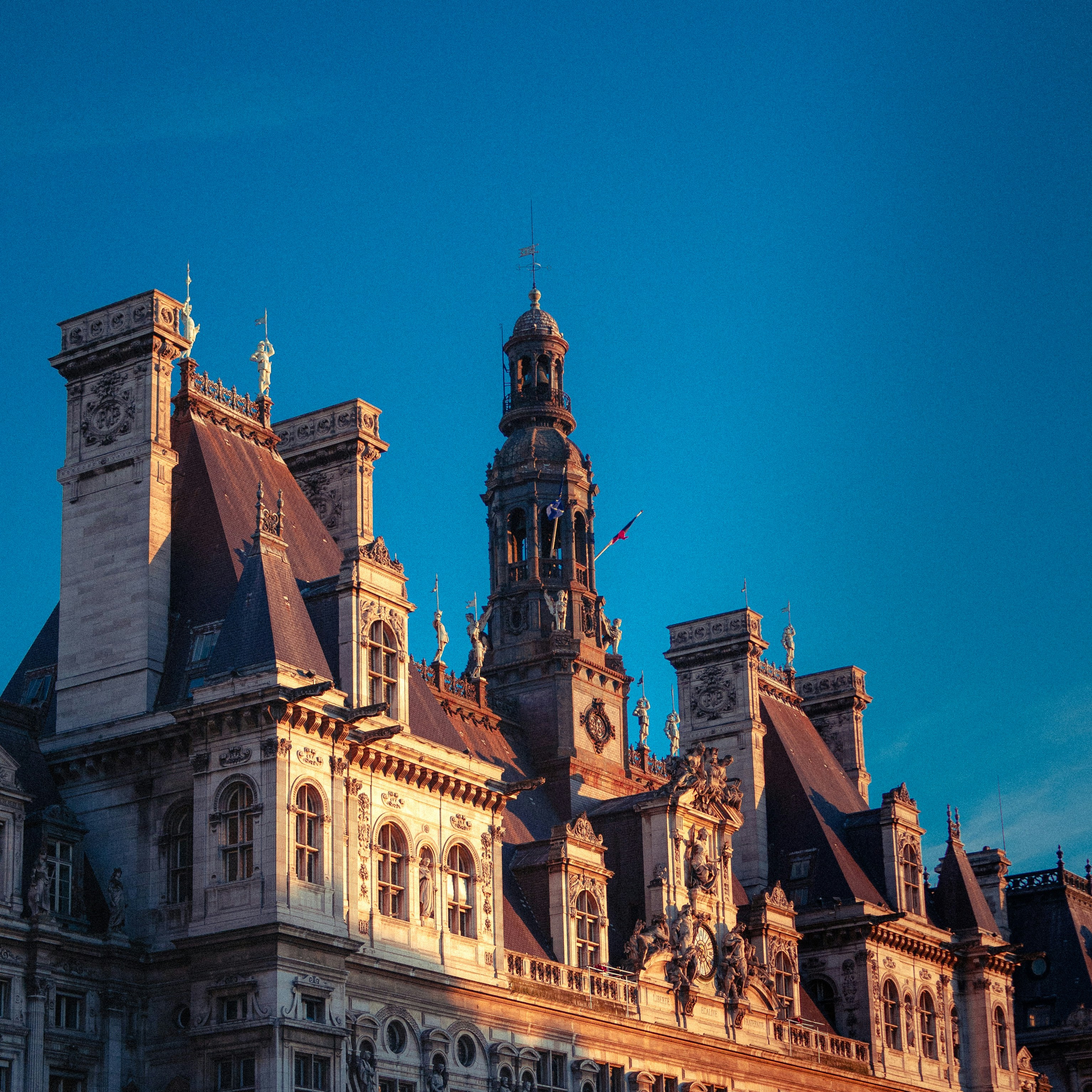 Historic city hall building with intricate architectural details illuminated by the warm glow of sunset.