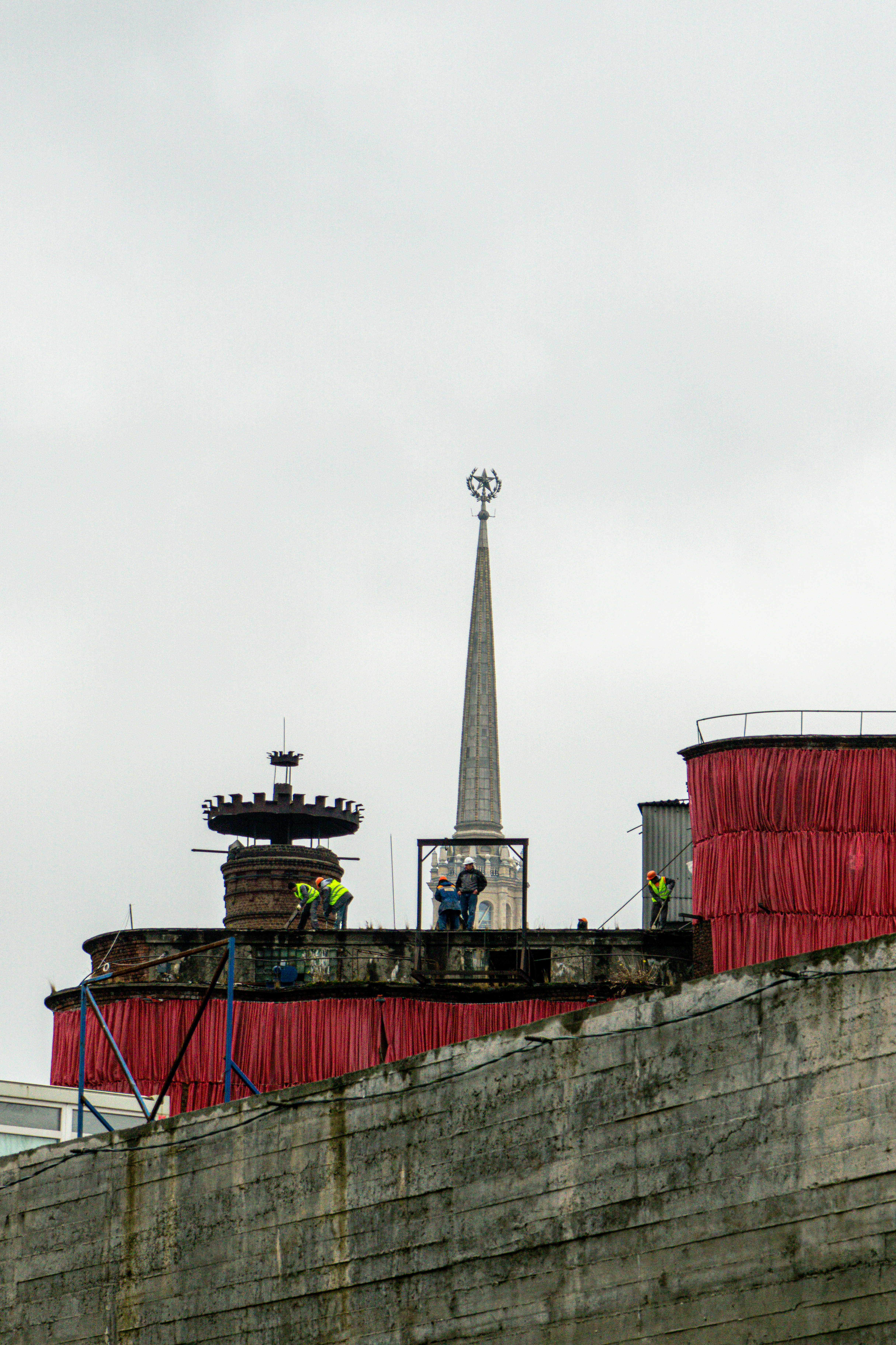 Rooftop Spireline: Neon-Vested Workers Beneath a Weathered Edge