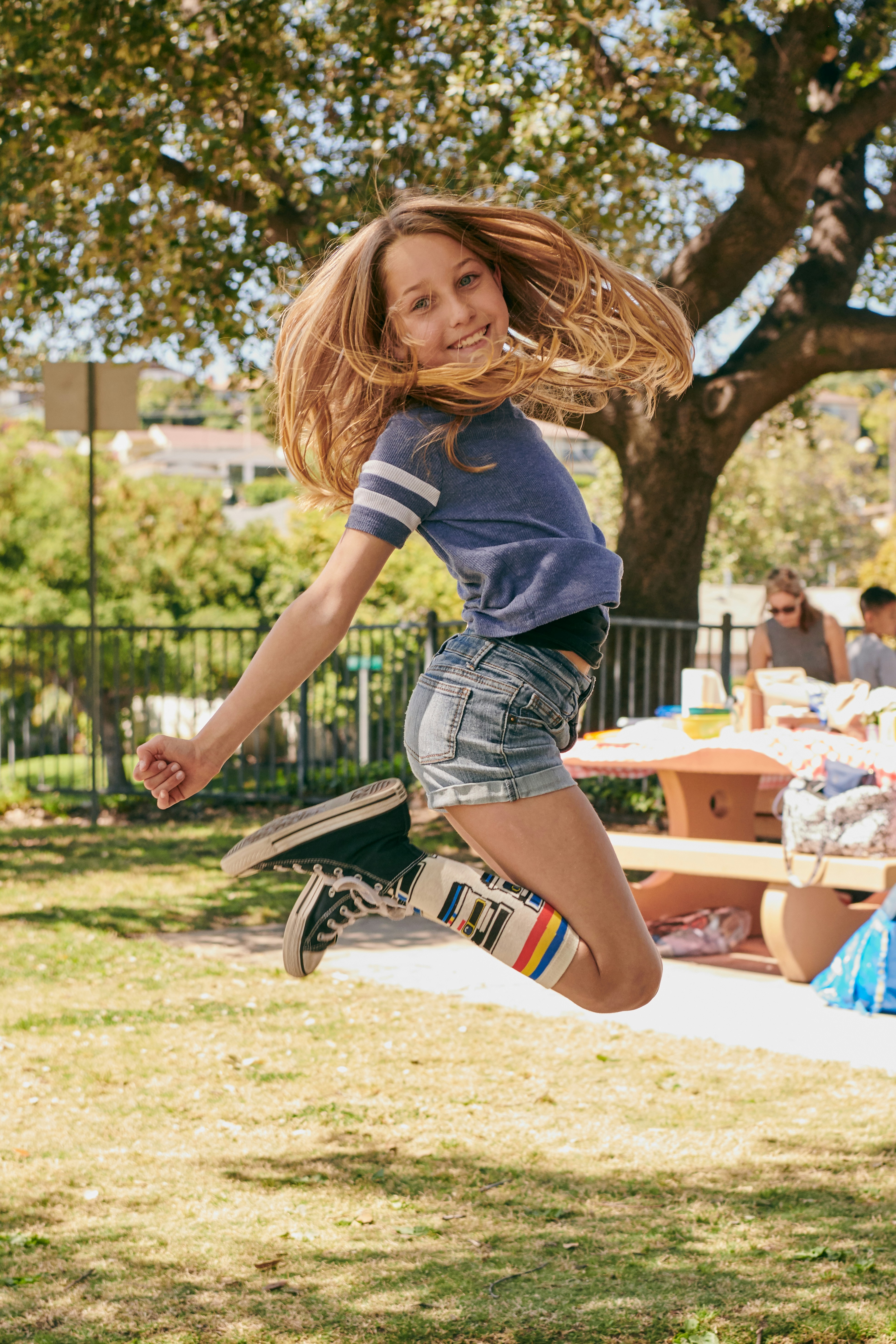 Leap of Joy: Girl in Midair at a Sunny Park Picnic