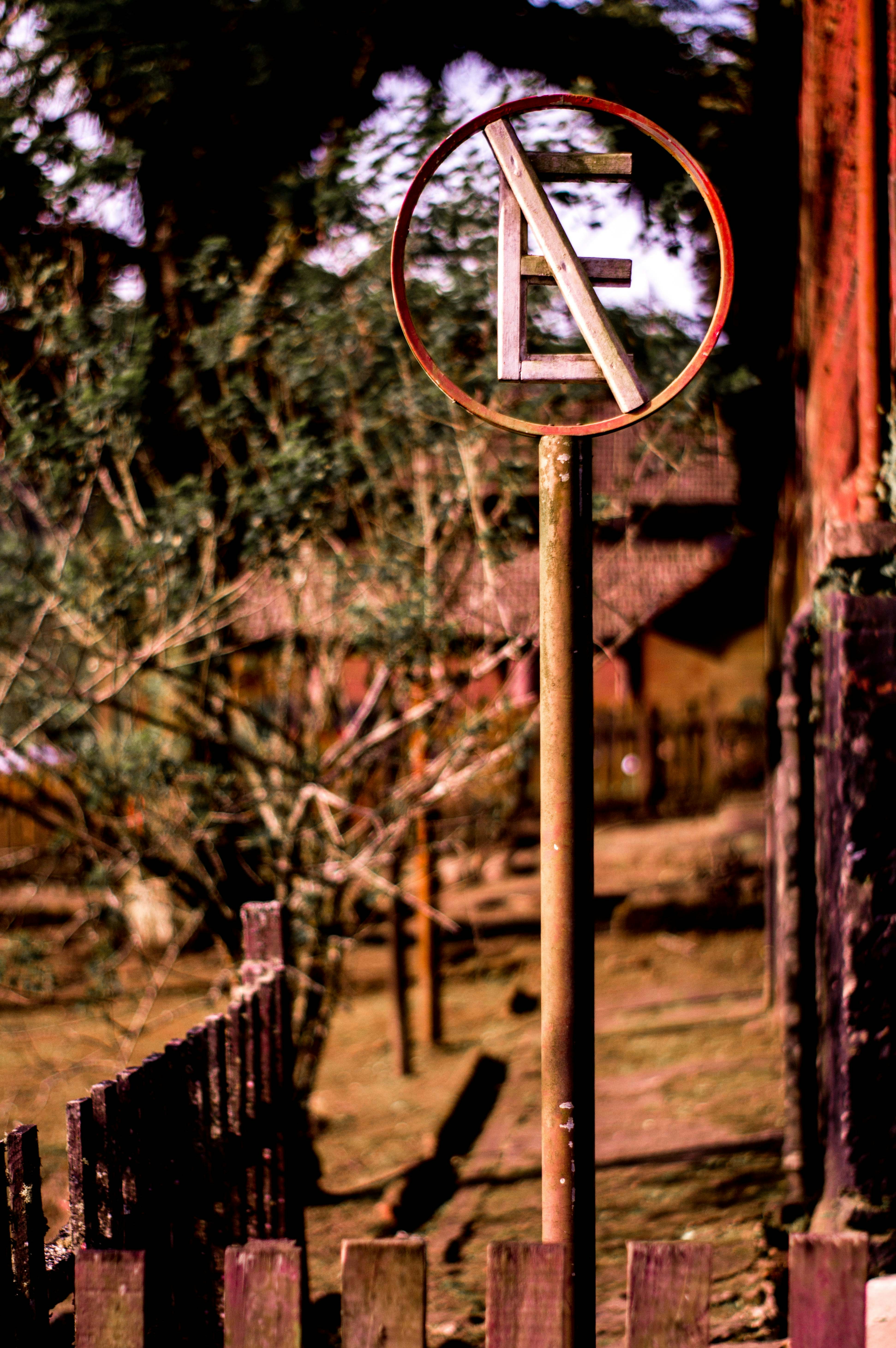 No parking sign stands resolute amidst a rustic setting, framed by trees and wooden fencing.