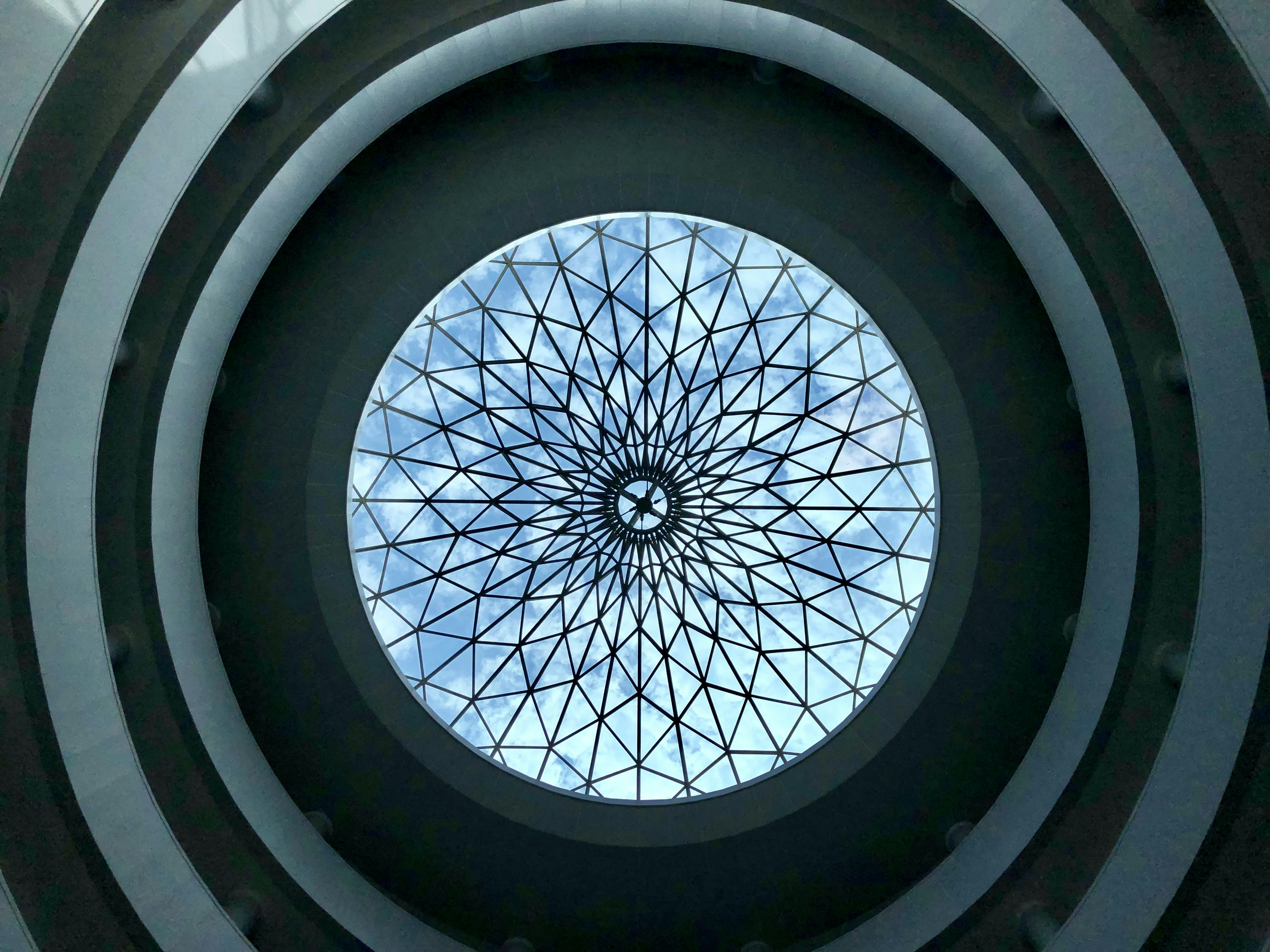 Intricate geometric pattern of a skylight, showcasing a web of glass and metal against a bright sky.