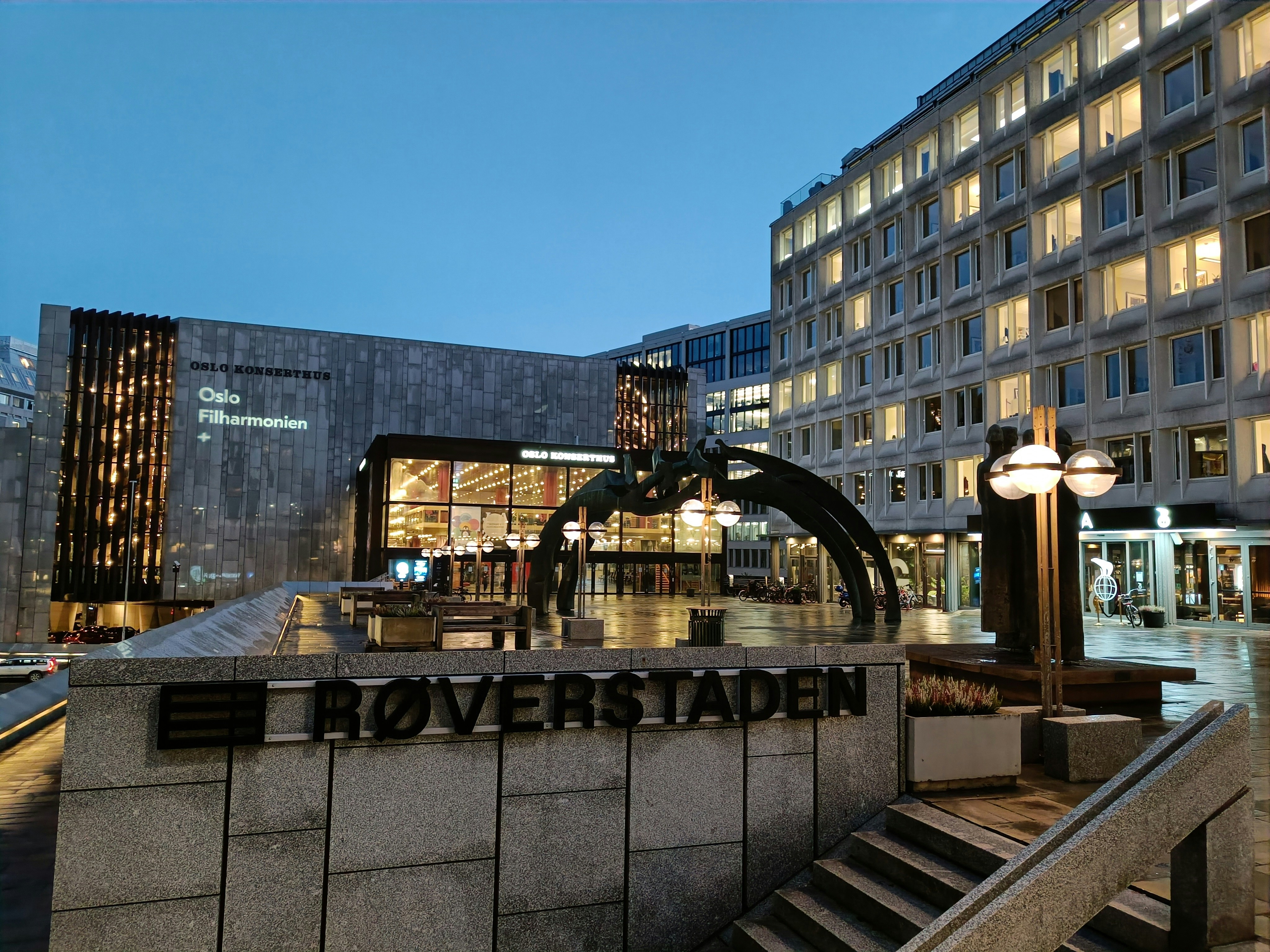 Modern architectural design of the Oslo Philharmonic Hall with sculptural elements in the foreground. Evening ambiance enhances the urban landscape.