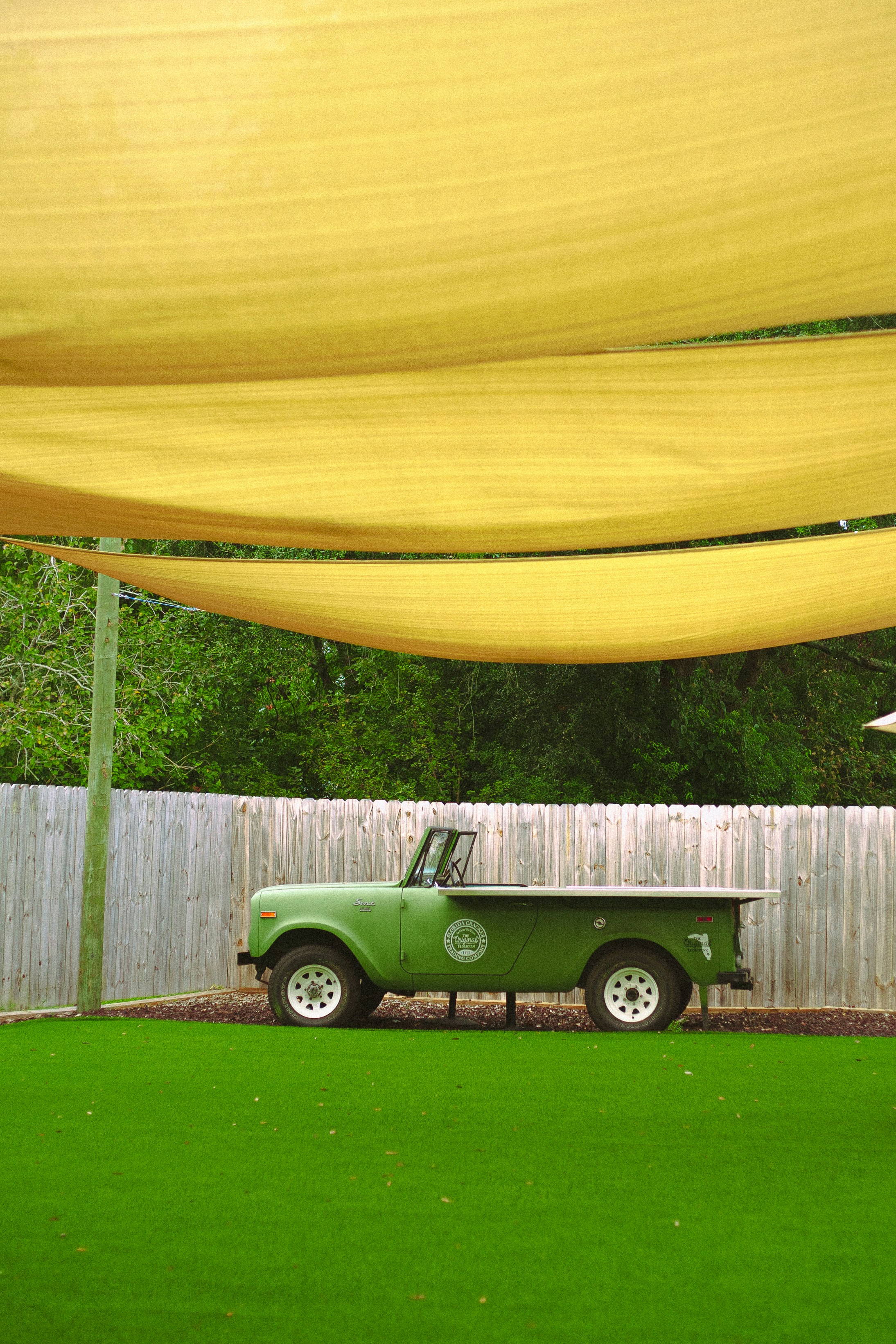 a green pick up truck parked under a yellow tarp