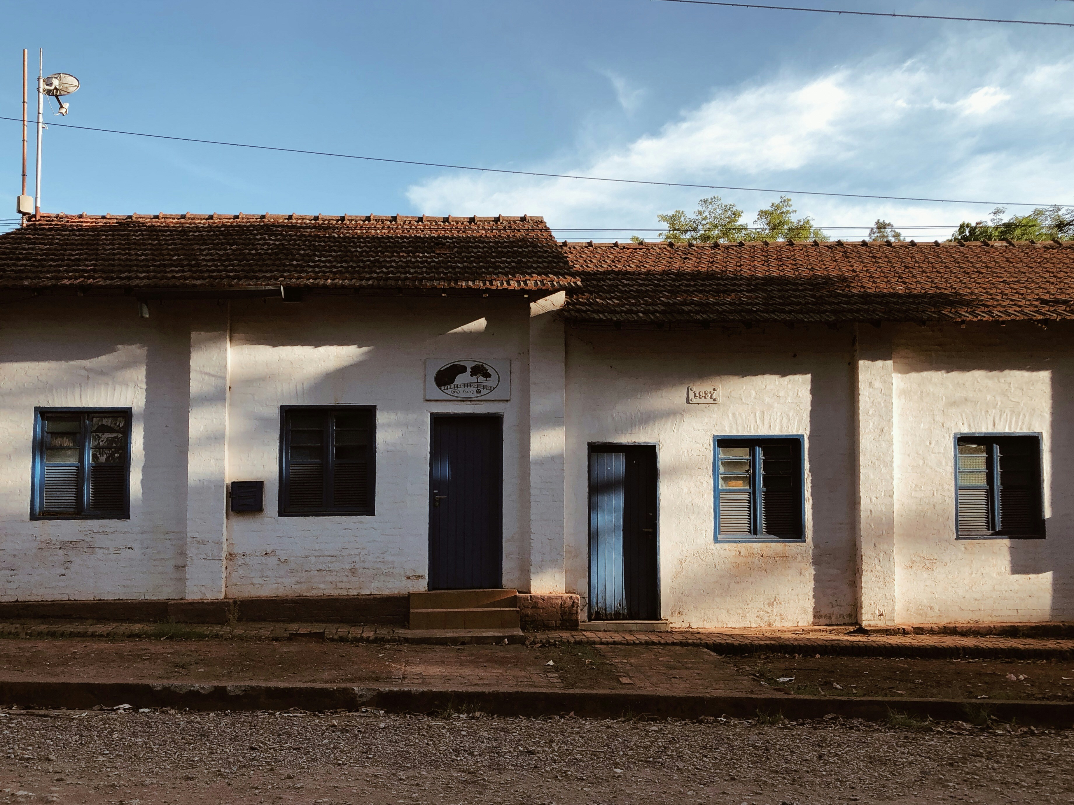 Weathered building with a rustic roof and multiple windows under a blue sky.