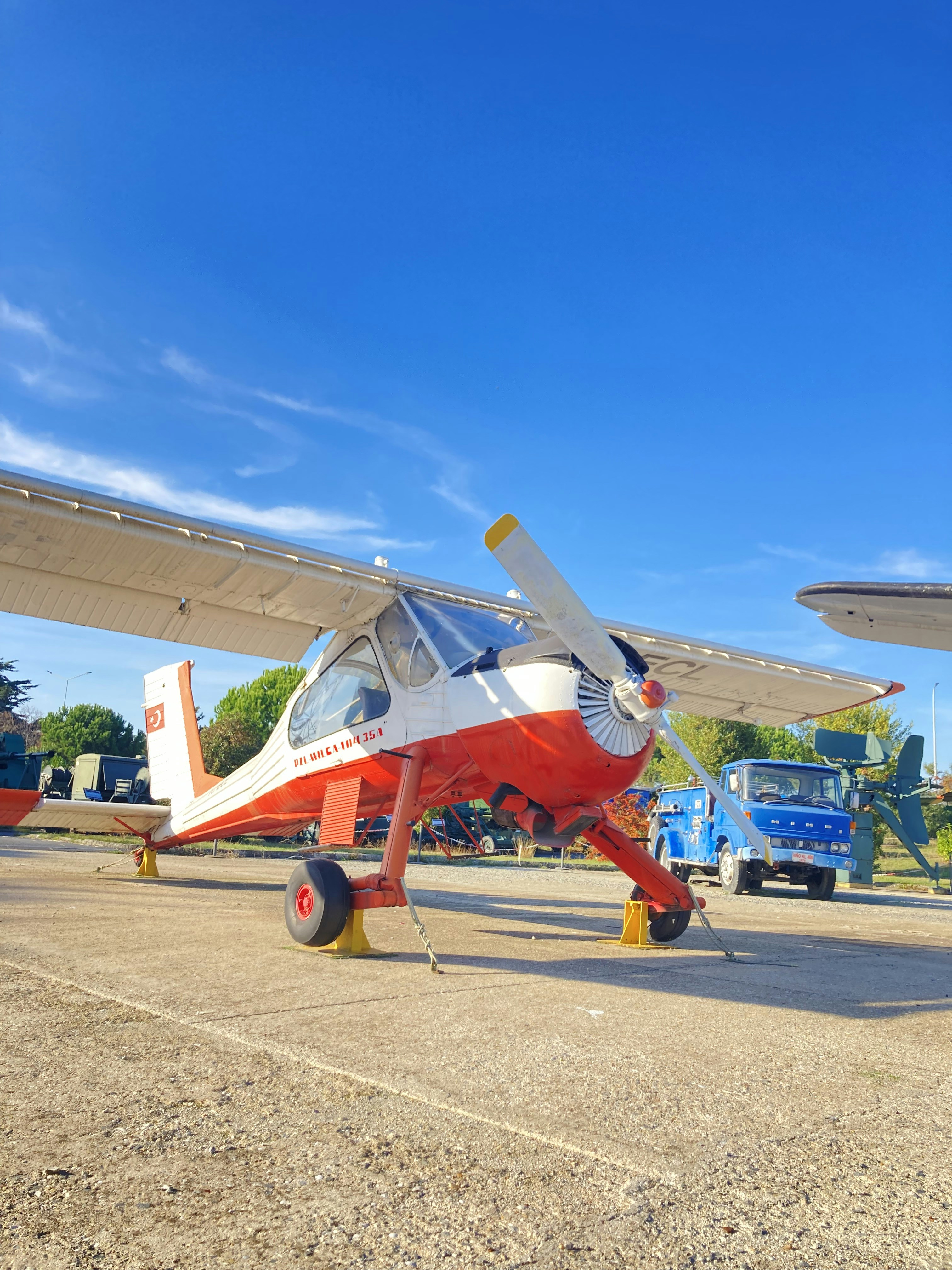 Grounded in Red and White: A Small Aircraft Resting Under a Clear Sky