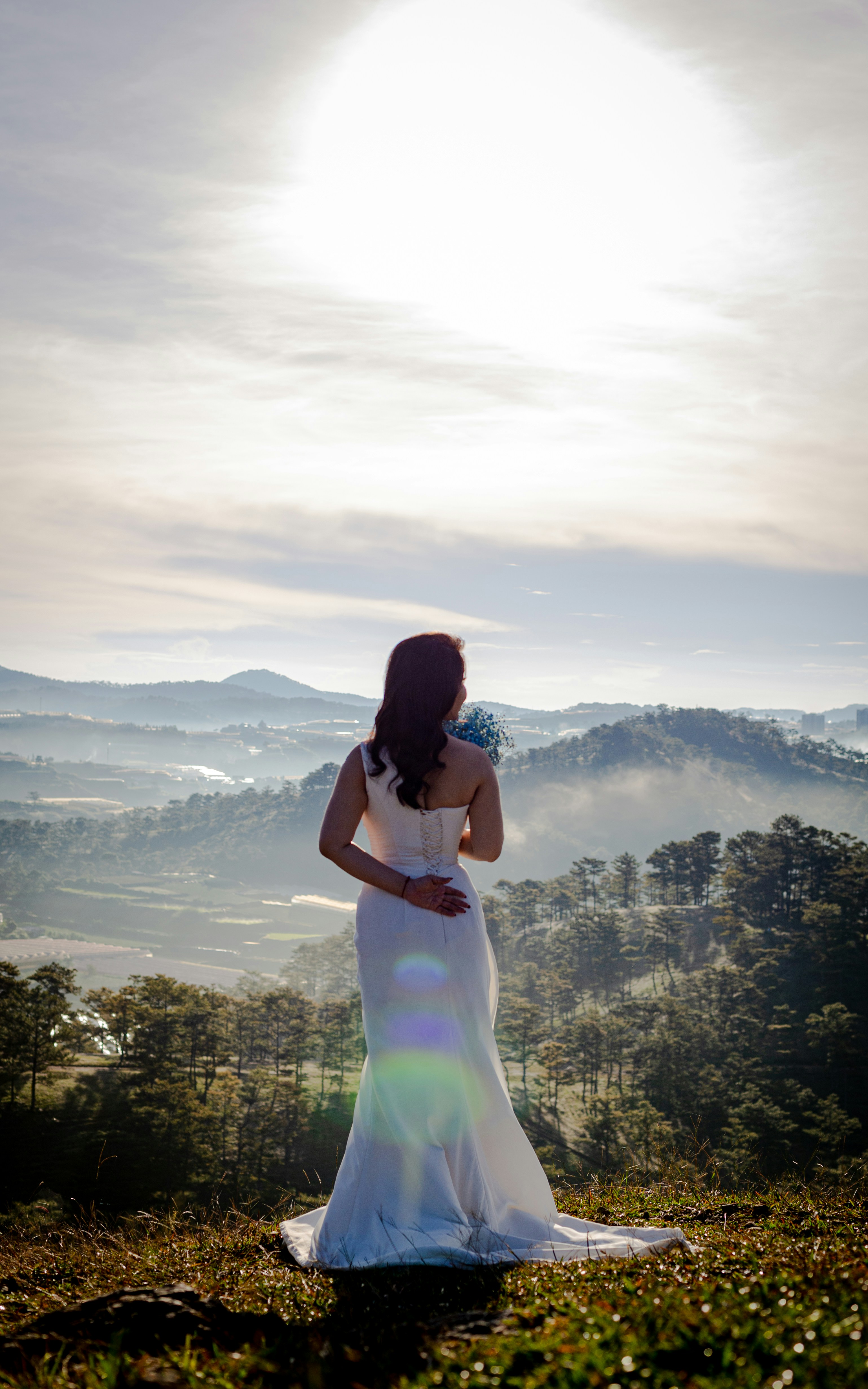 Bridal silhouette atop sunlit hills: a quiet vow against the valley haze