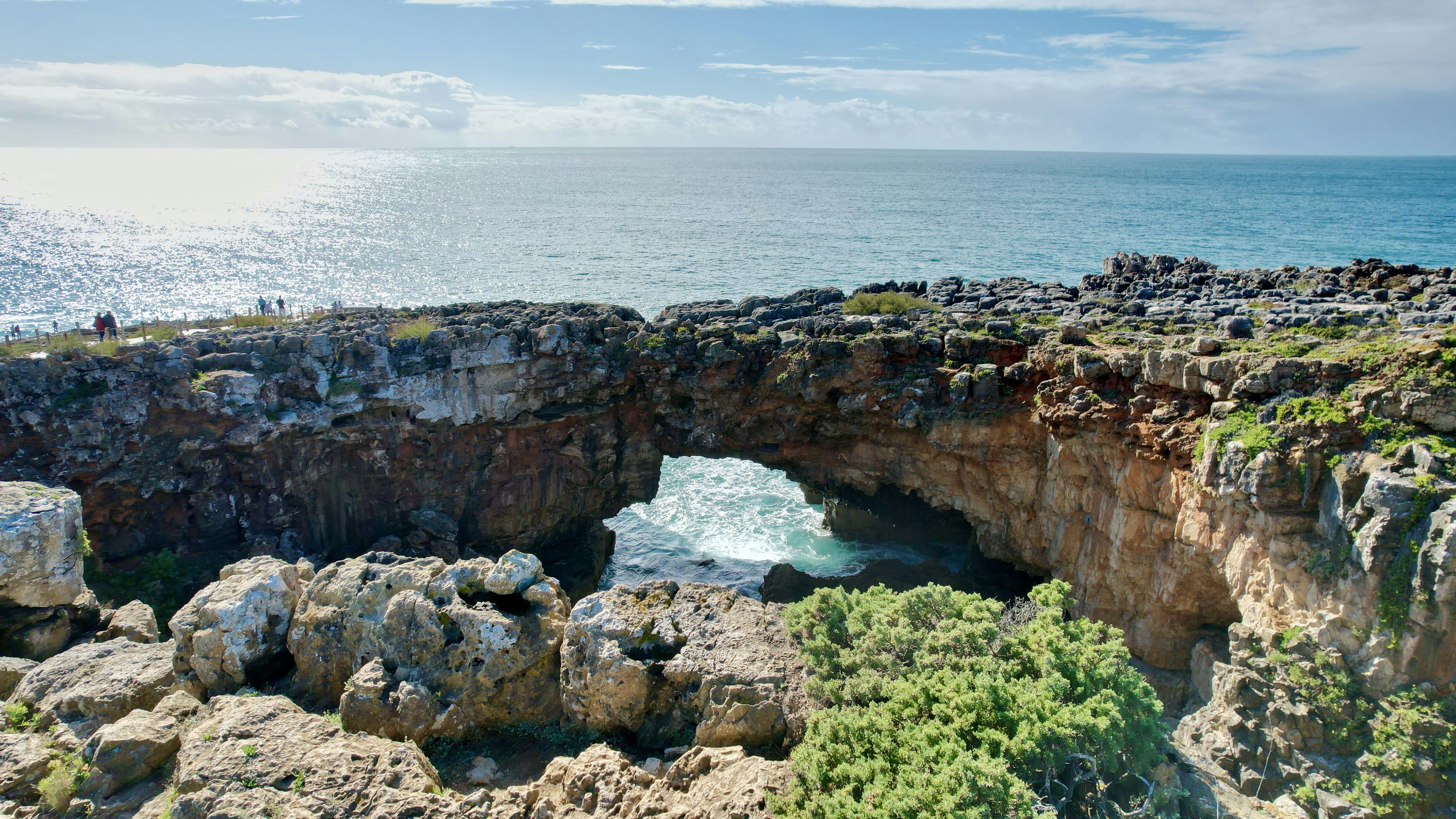 Oceanic Arch: Sunlit Cliff Hole Framed by Azure Sea