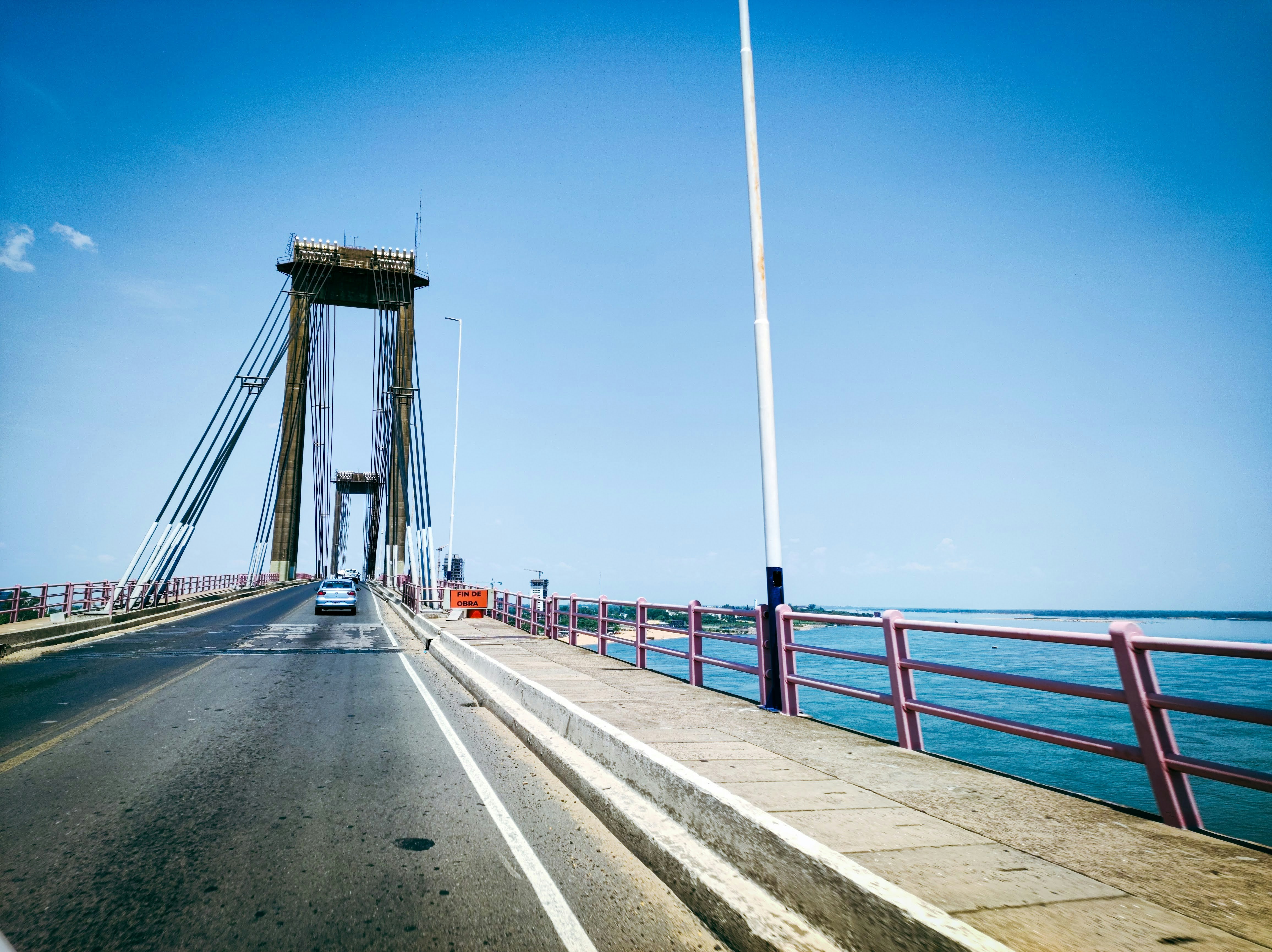 Suspension bridge spanning over blue waters under a clear sky.