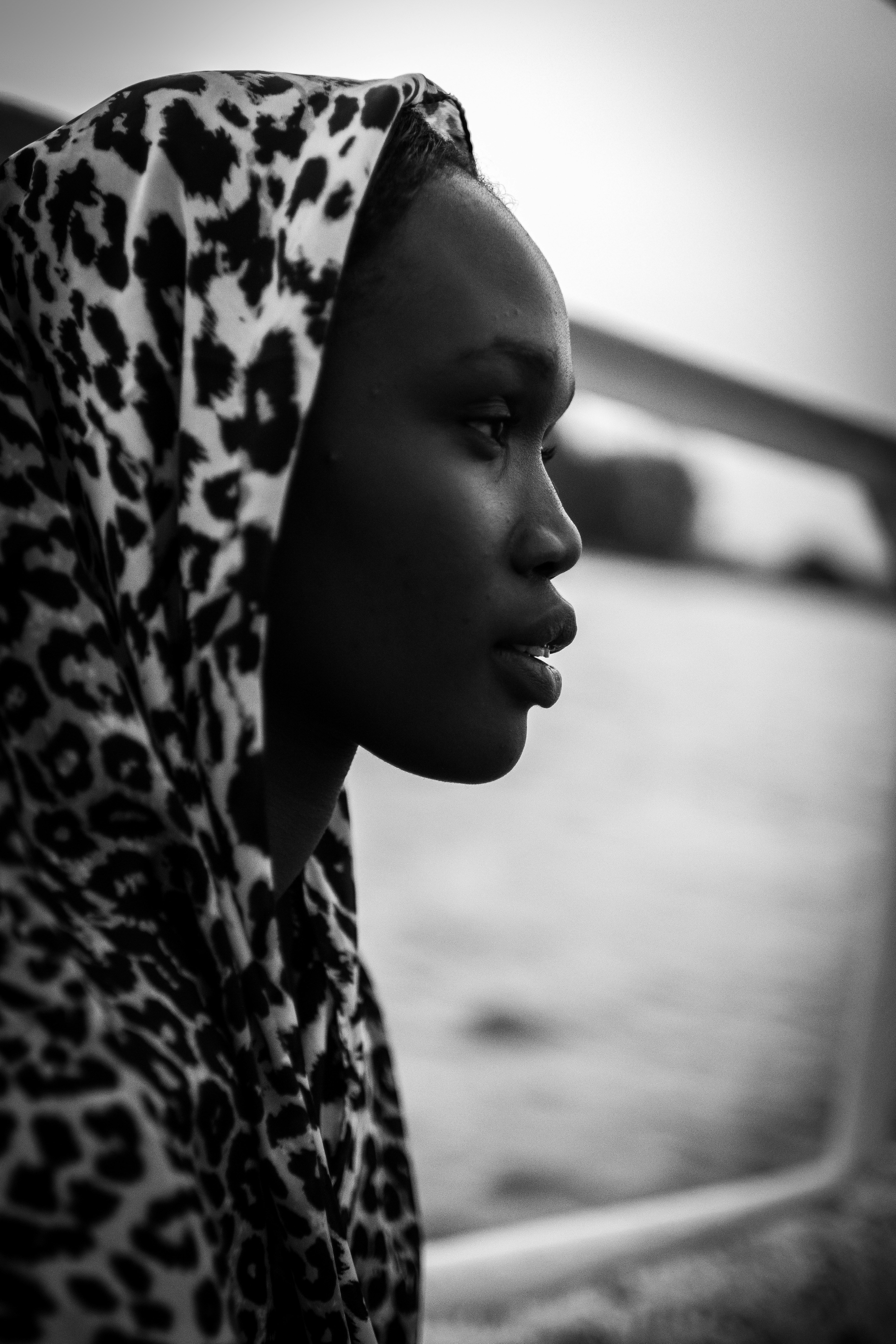 Monochrome black South Sudanese girl in leopard print hijab stares out across the river NileMichael Starkie
