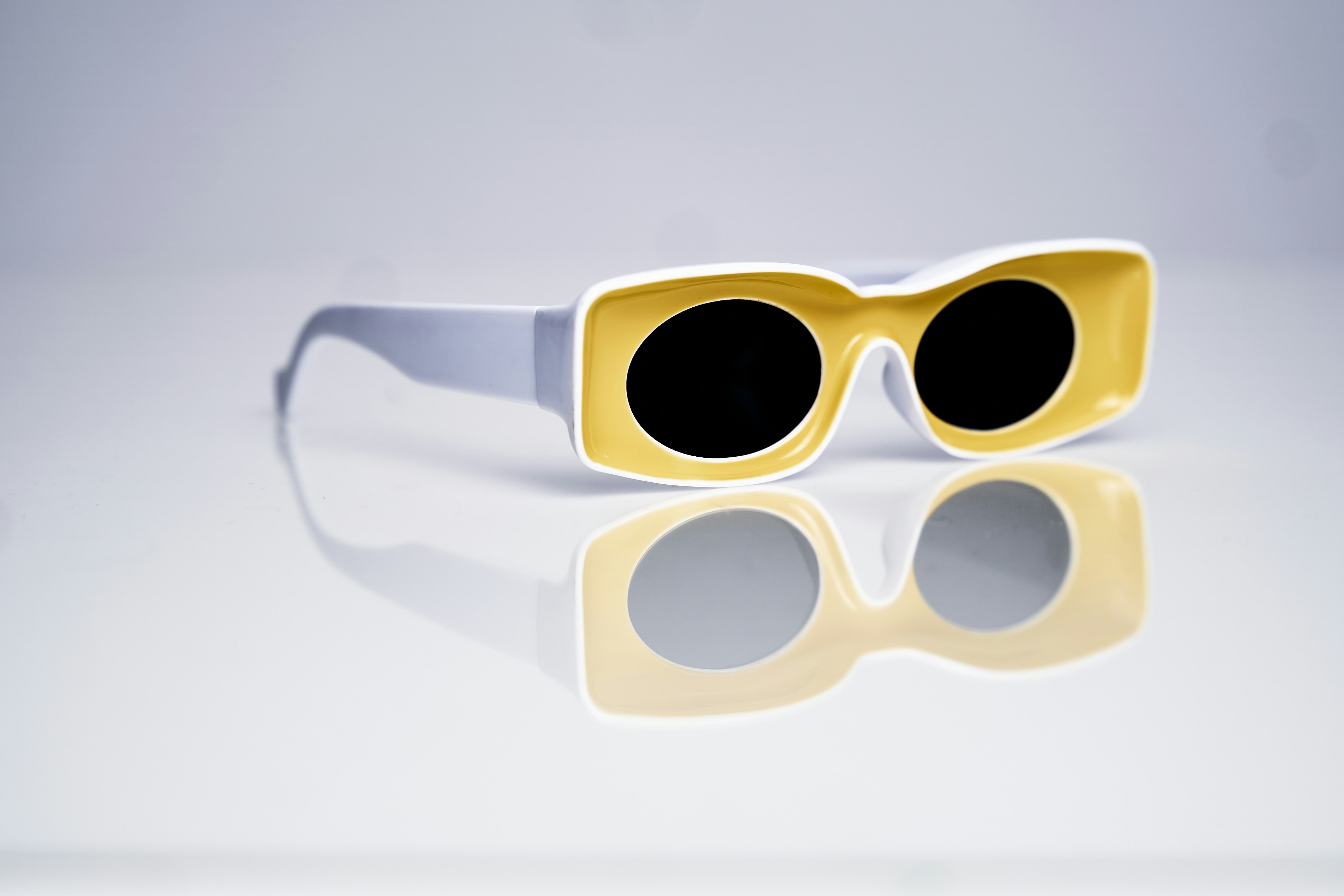 Yellow-framed sunglasses resting on a reflective surface