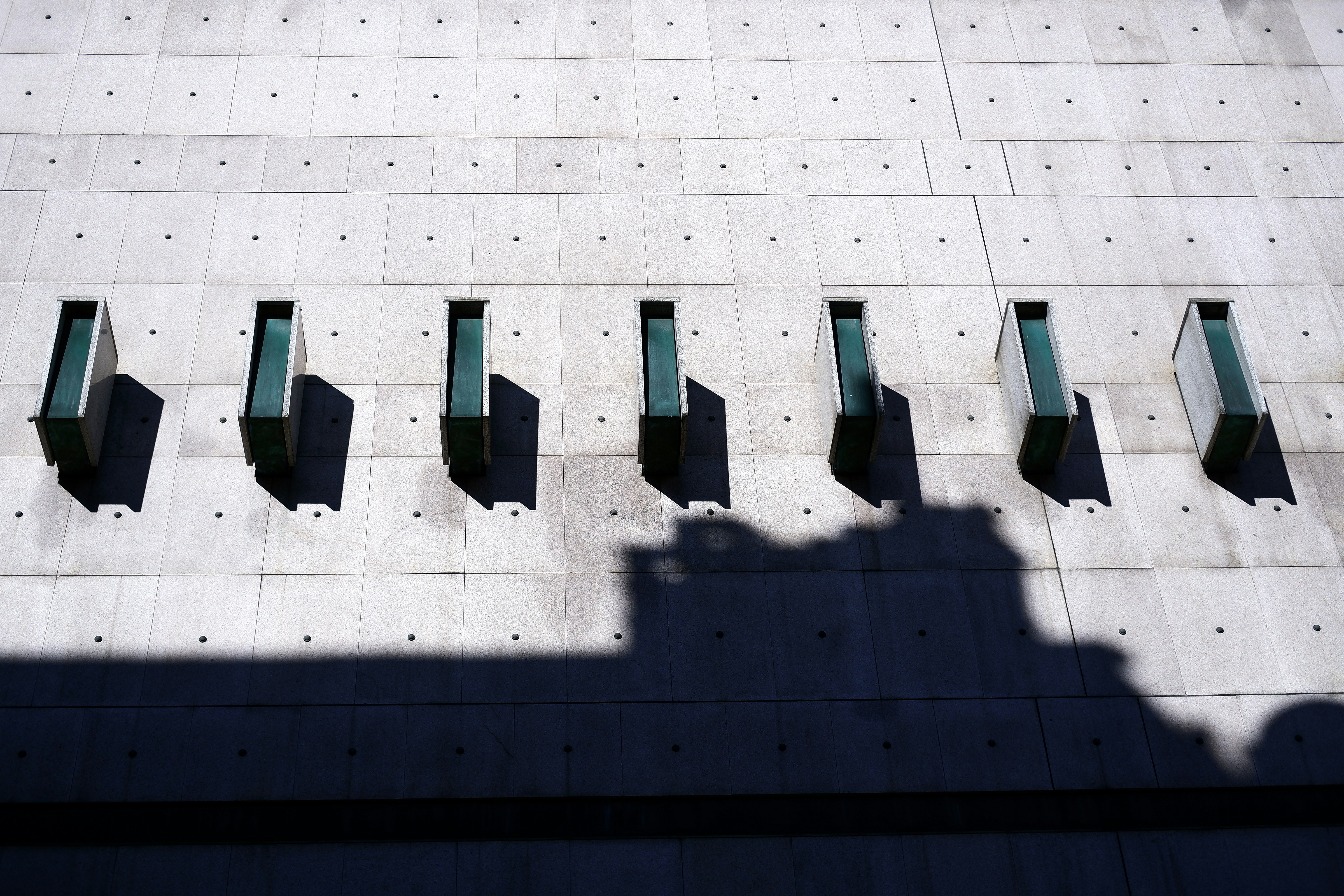 Vertical Verdigris: A Row of Green-Glass Louvers on Concrete