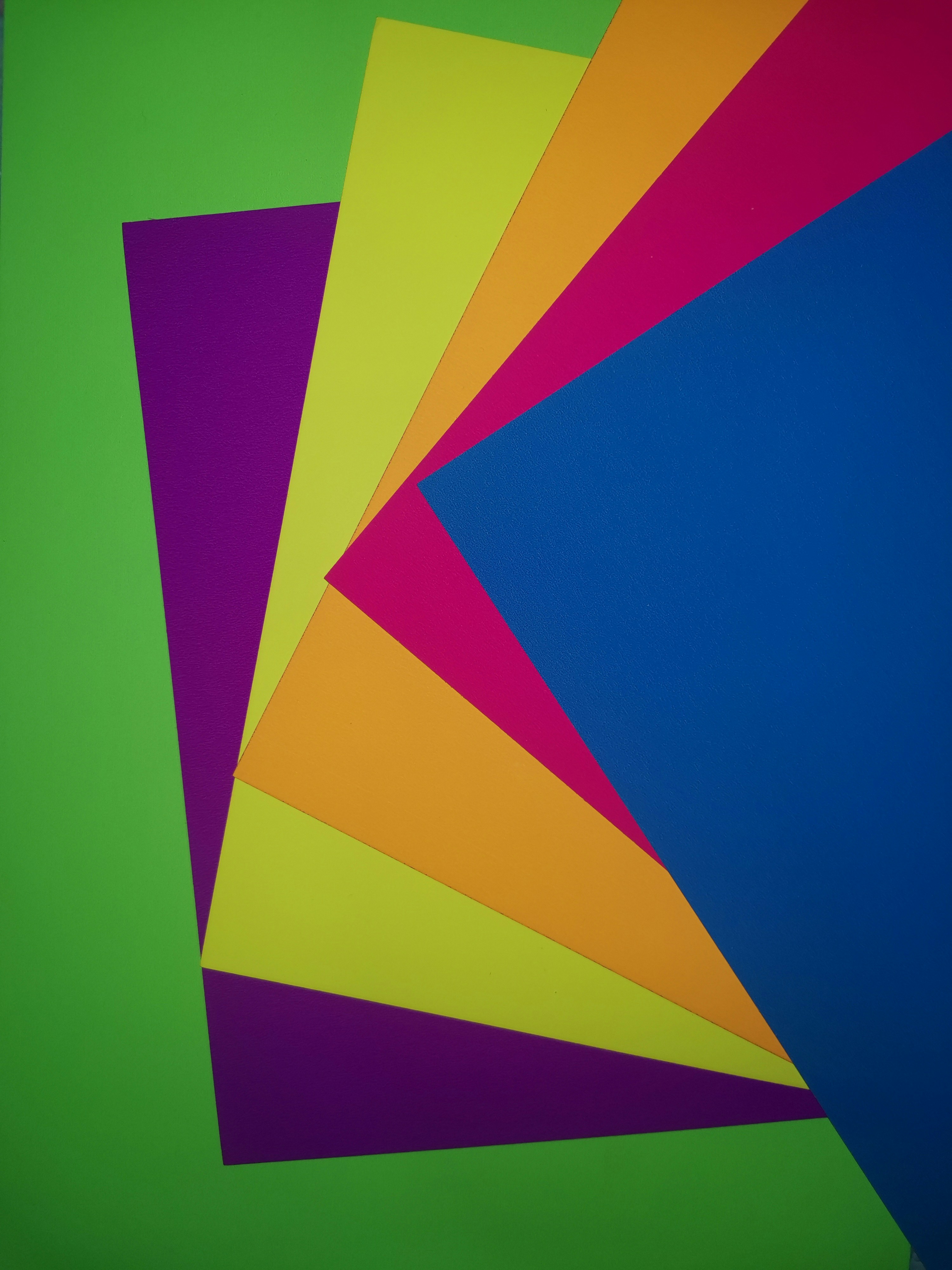 A vibrant arrangement of colored sheets, featuring green, purple, yellow, orange, pink, and blue, layered artistically to create a visually appealing composition.